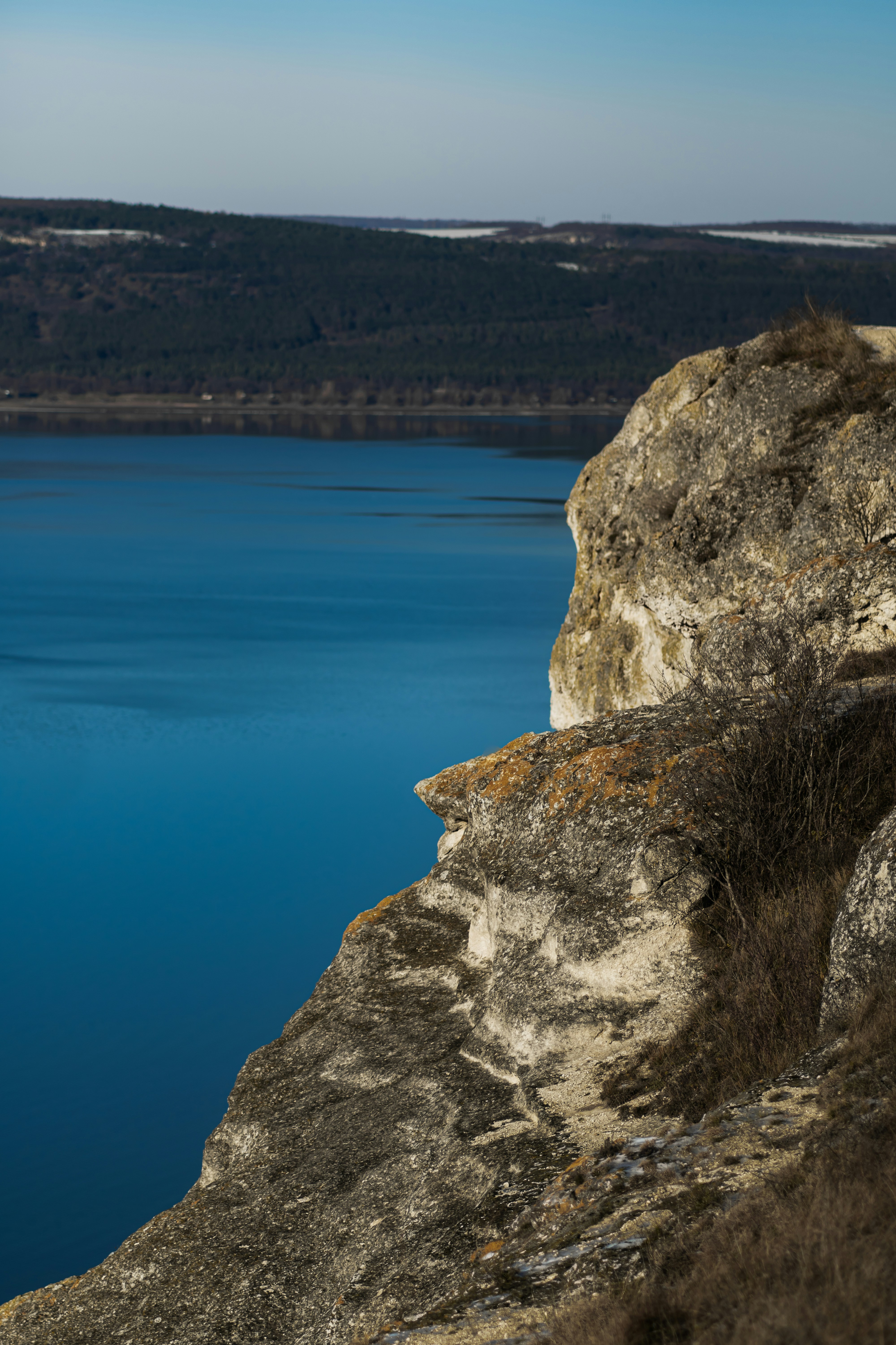 Rocky cliff overlooks a beautiful, blue body of water. photo – Free ...