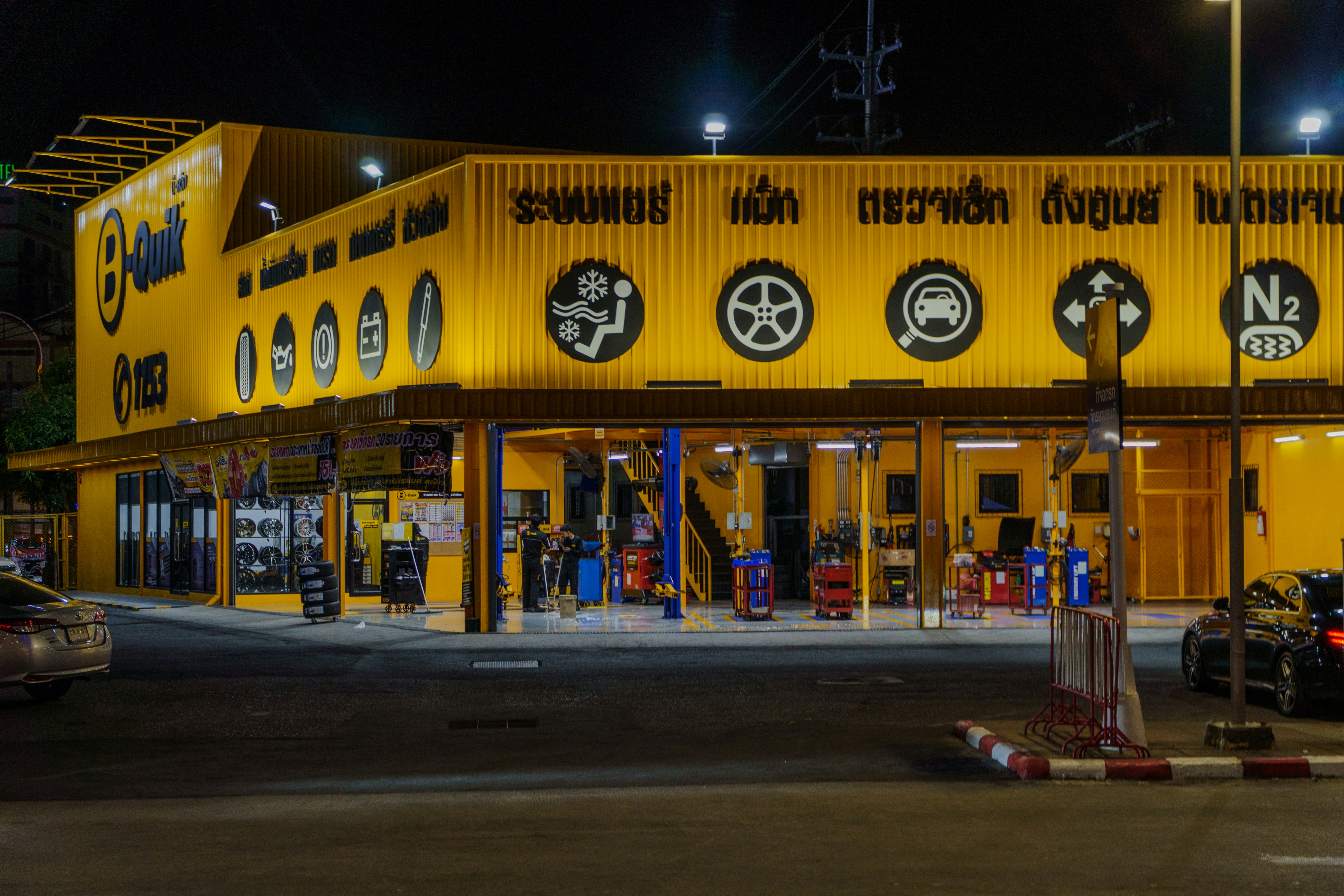 A brightly lit yellow auto repair shop at night. photo – Free Car Image ...