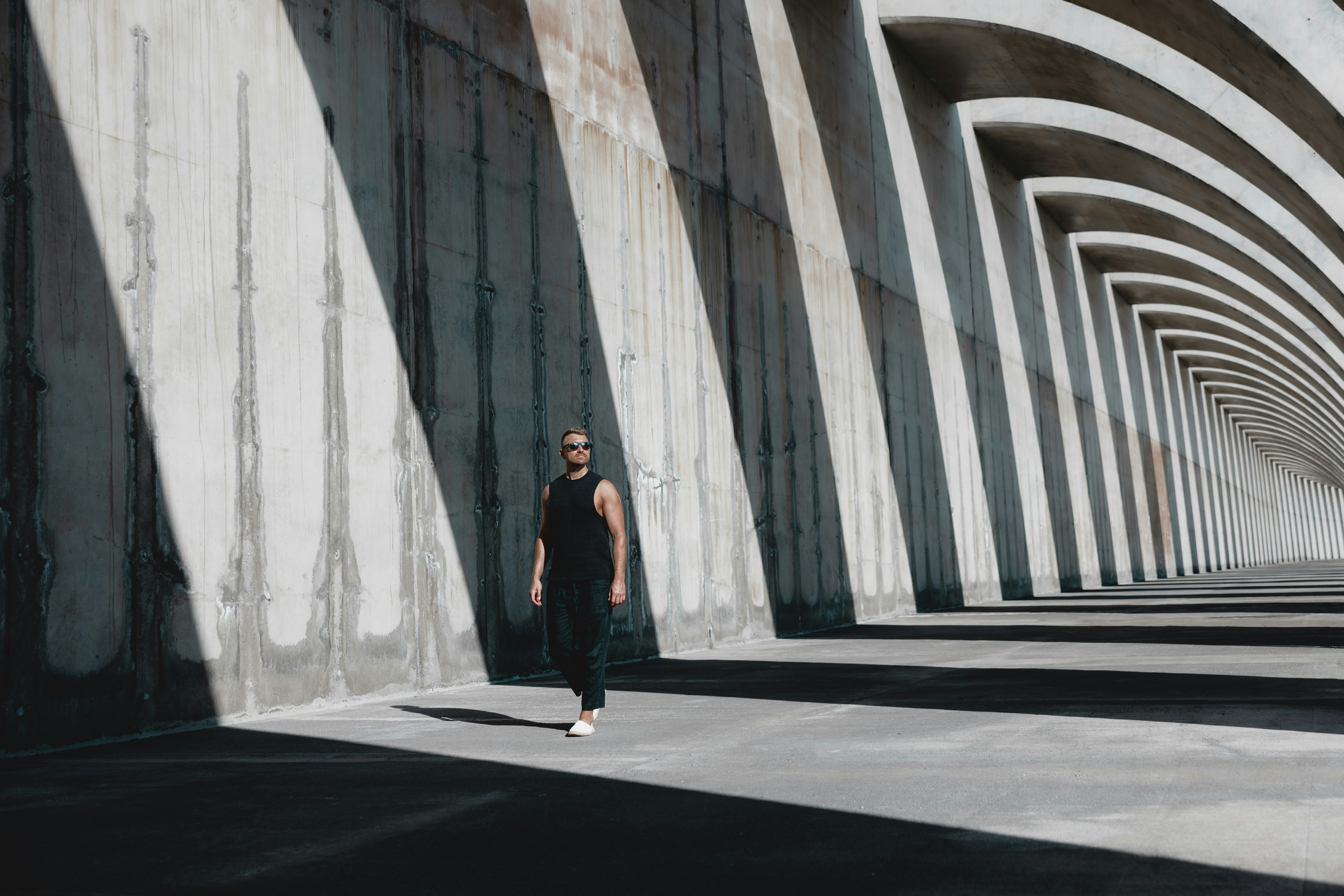 A man walks through a modern, shaded structure. photo – Free Human ...