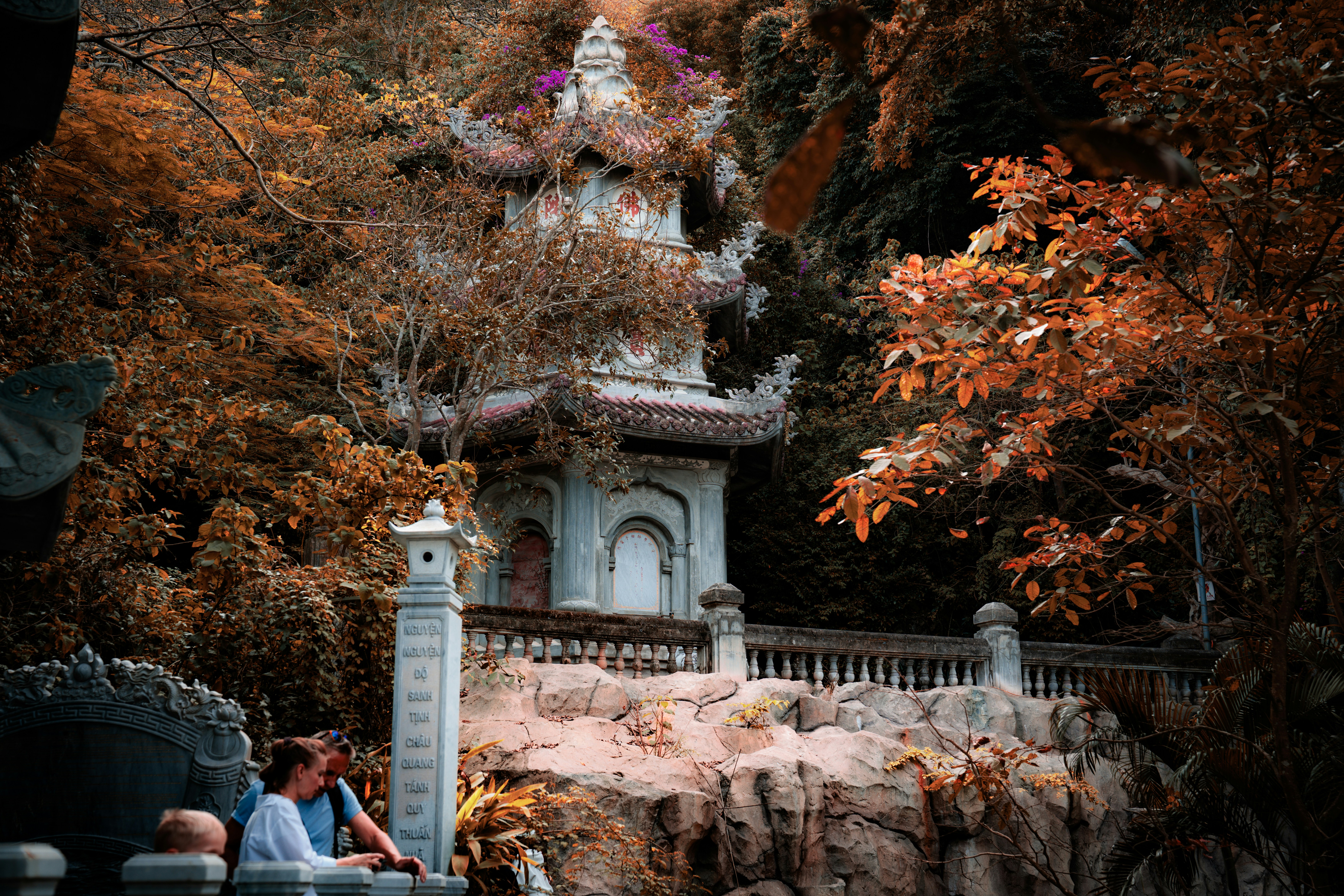 Ancient temple nestled amidst autumn foliage with vibrant orange and brown leaves.