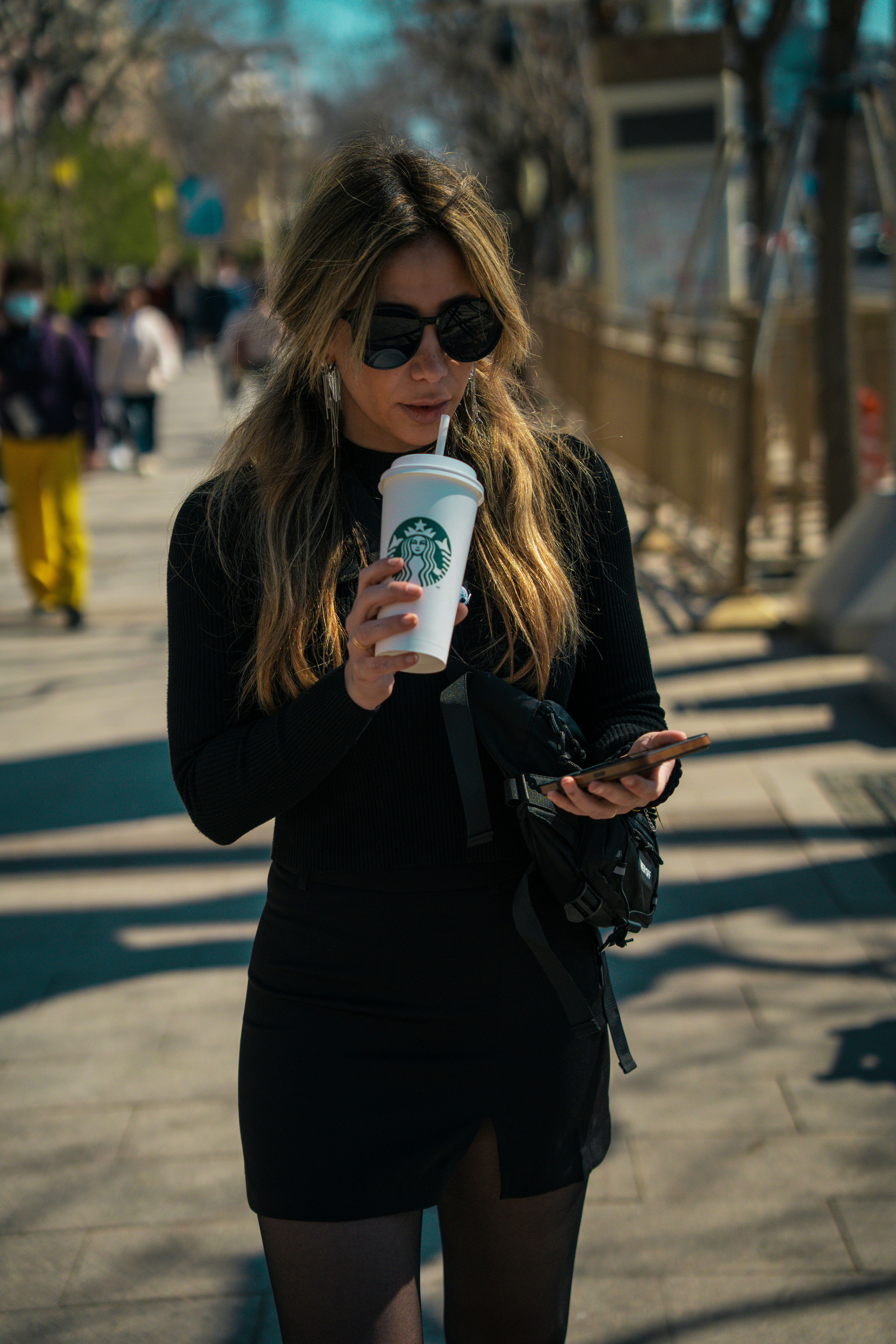 Woman sips starbucks while holding her phone. photo – Free Portrait ...