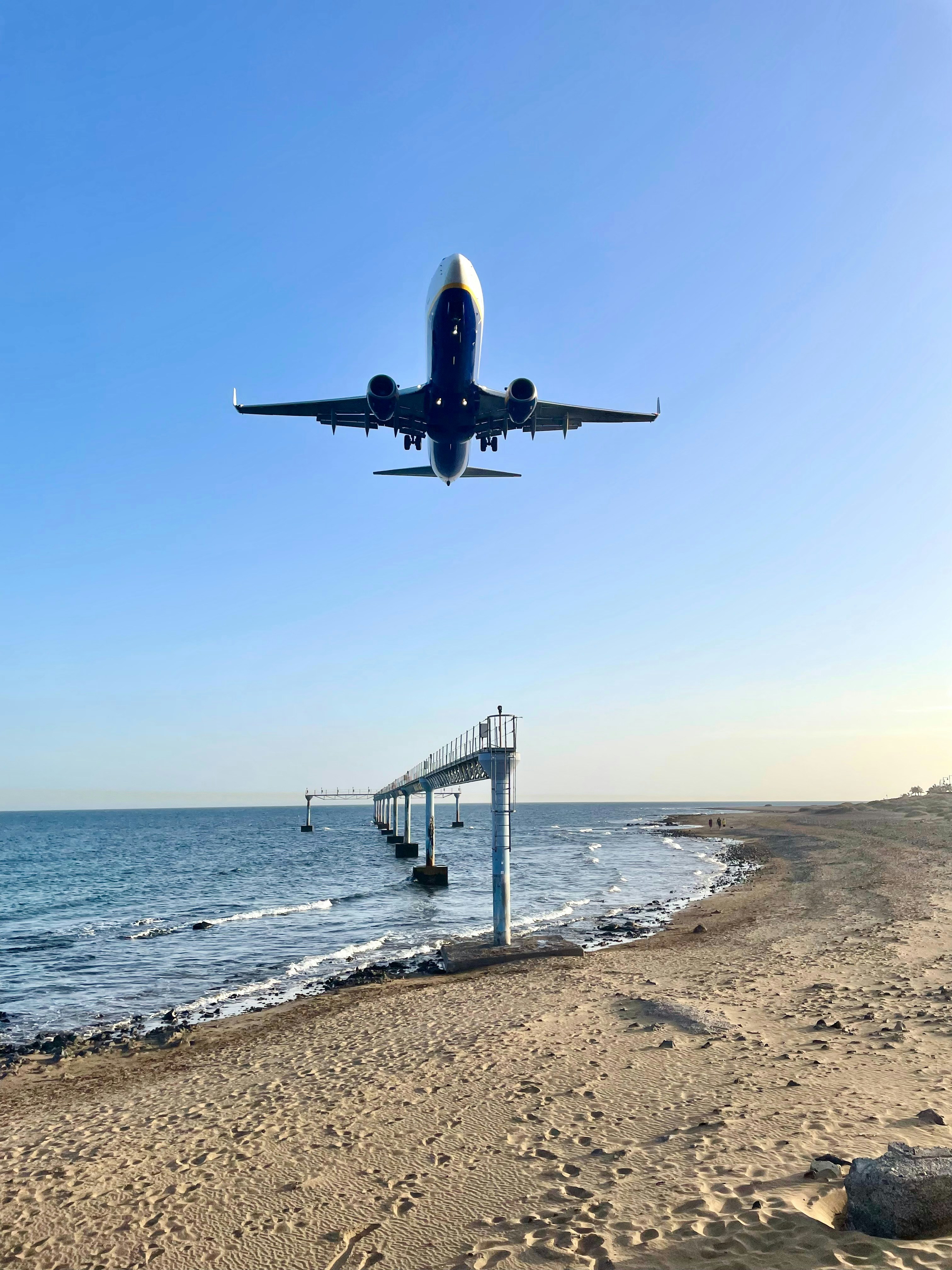 Azure Descent: A Jetliner Approaches a Quiet Seaside Pier