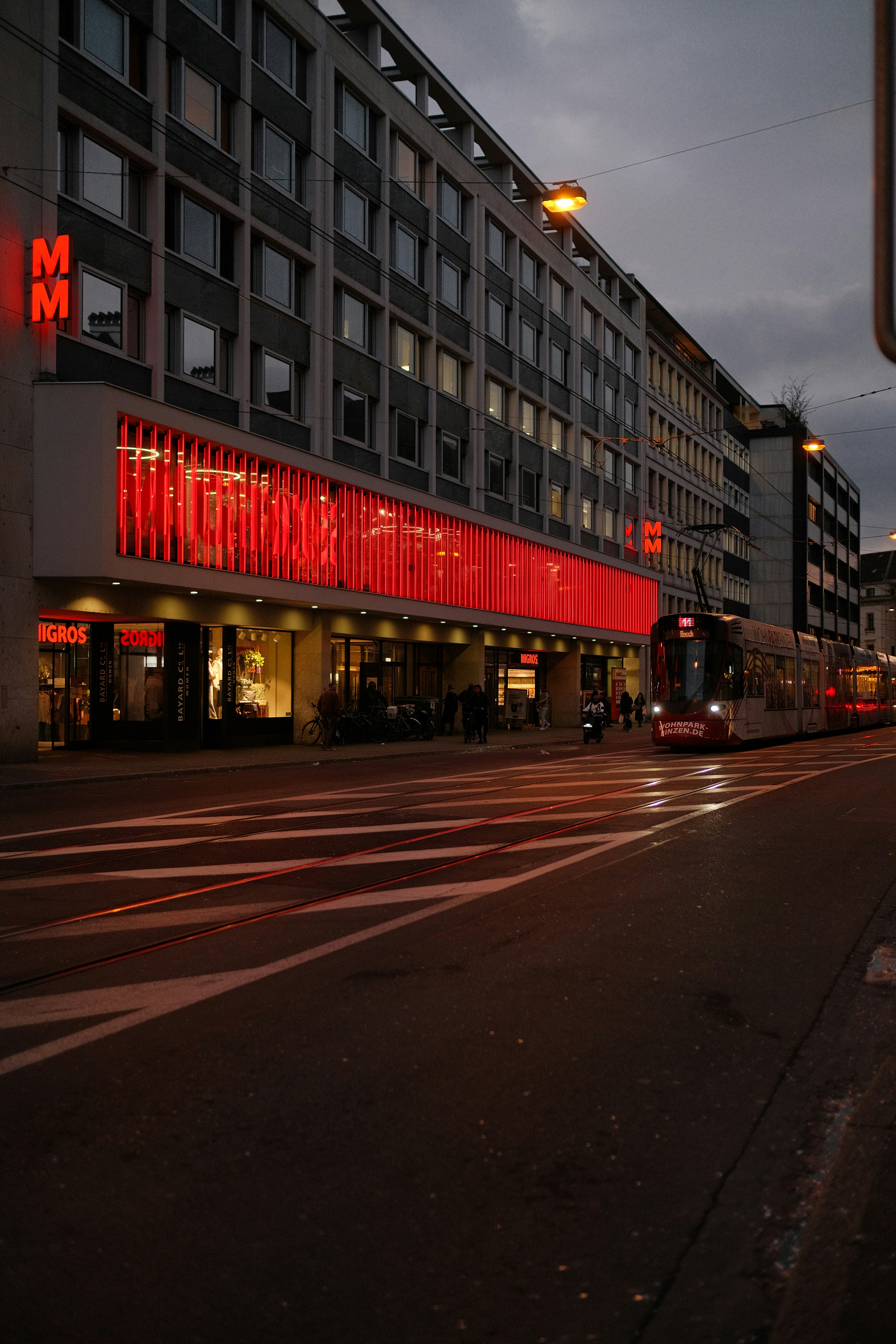 Crimson Neon Corridor: A Streetcar Traces the Dusk
