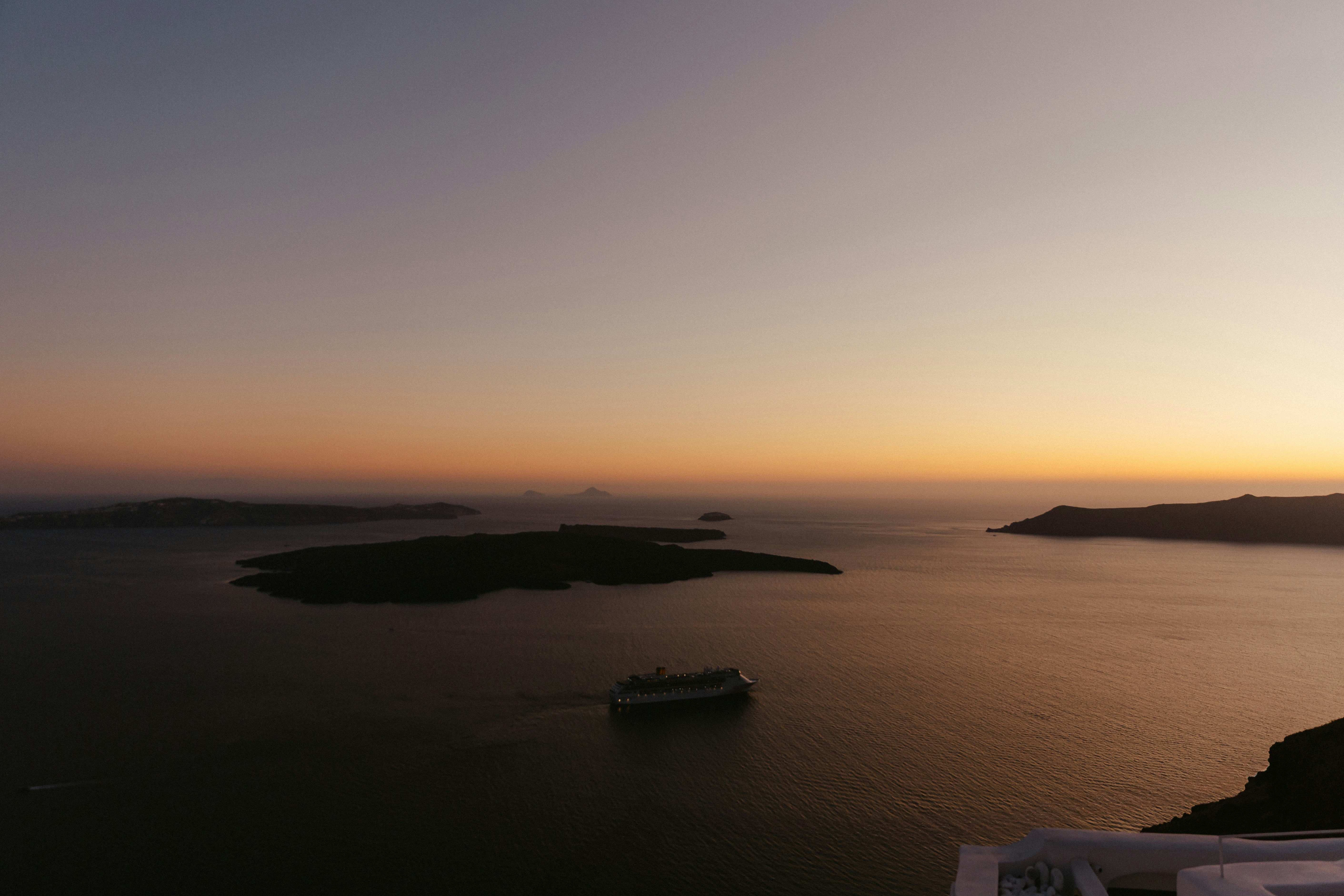 Amber Horizon: A solitary ferry gliding past silhouetted islets at dusk