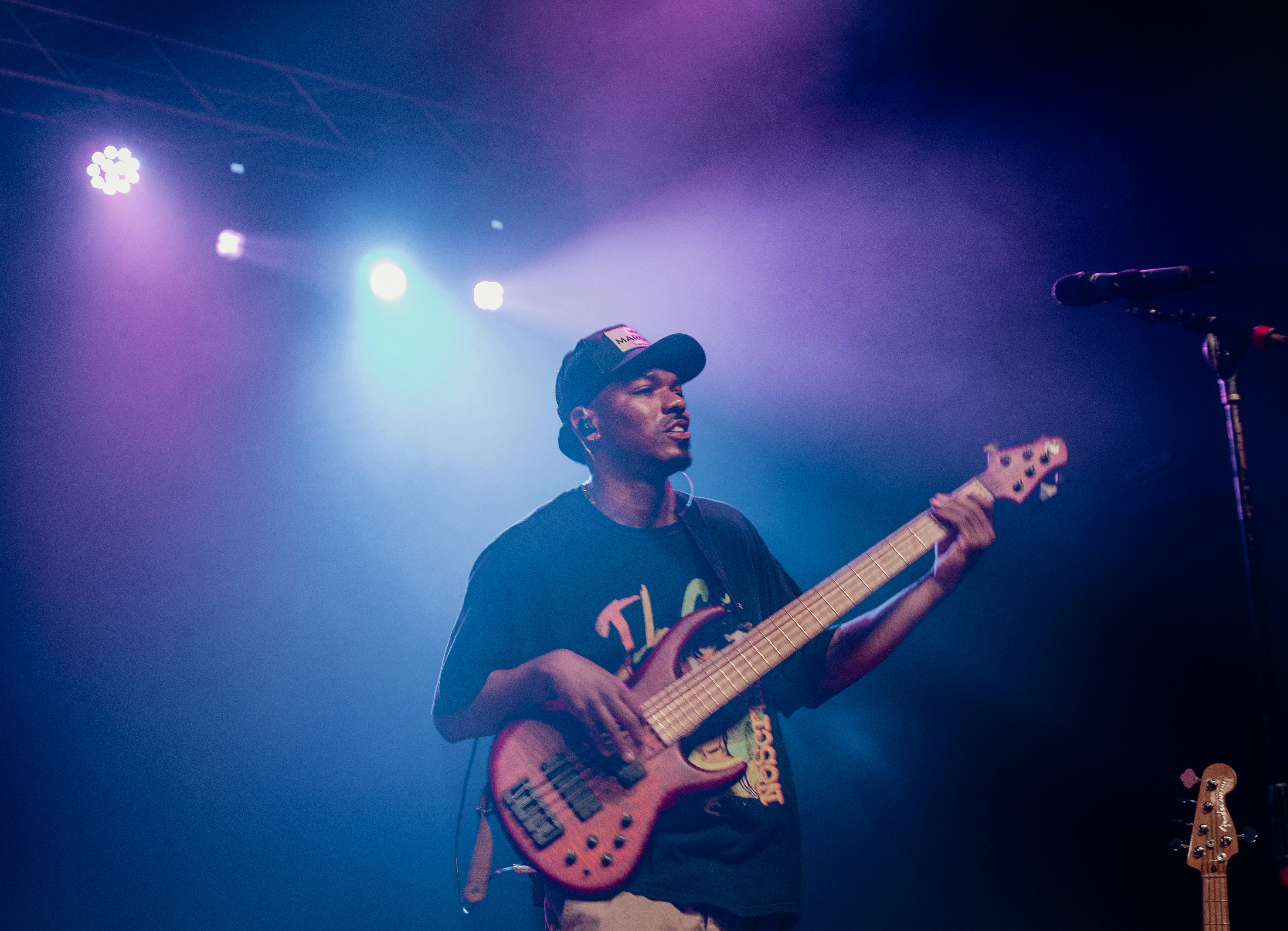 Musician playing bass guitar under vibrant stage lights during a live performance.