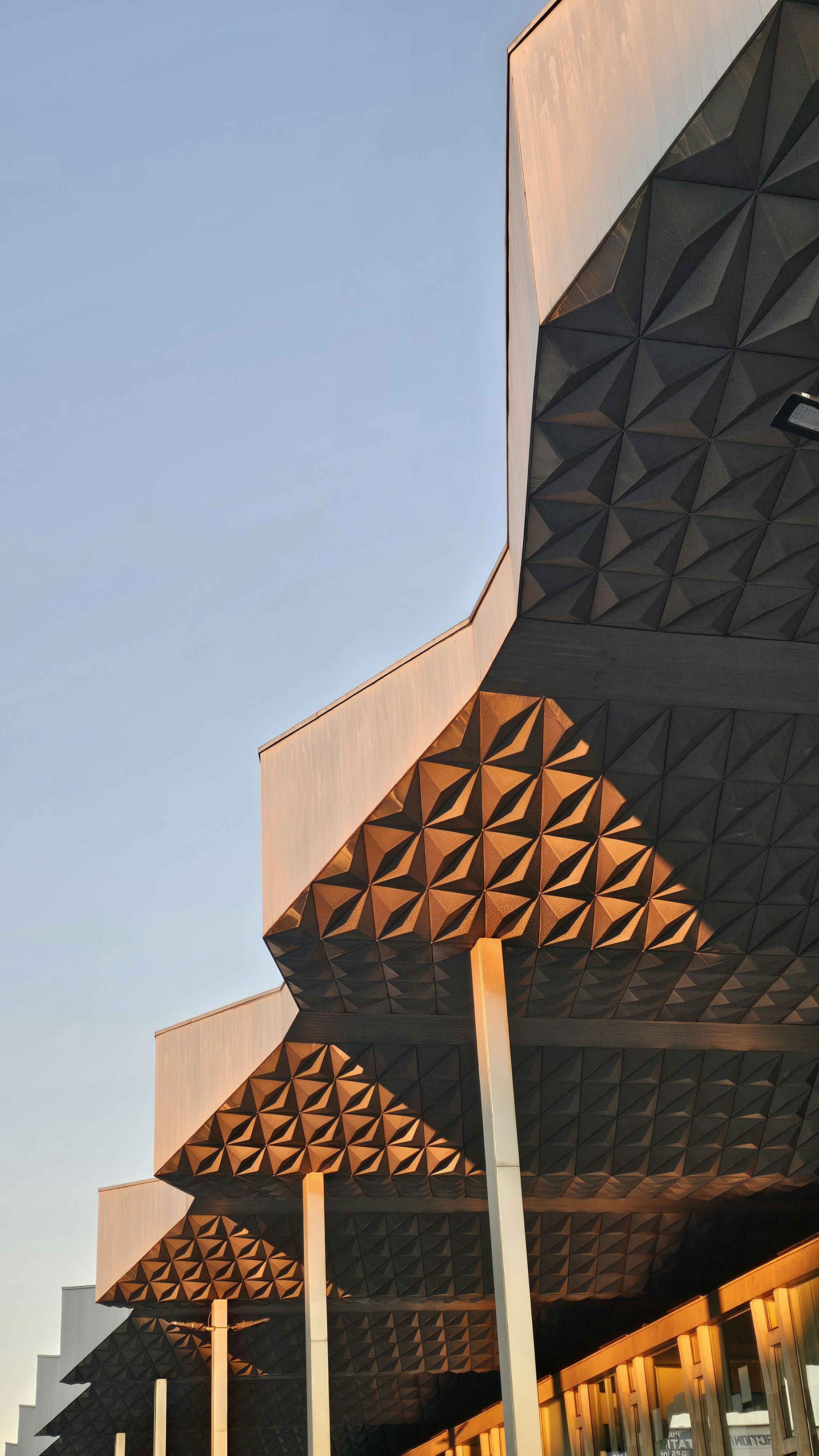 Architectural facade with geometric patterns illuminated by the warm glow of sunset.