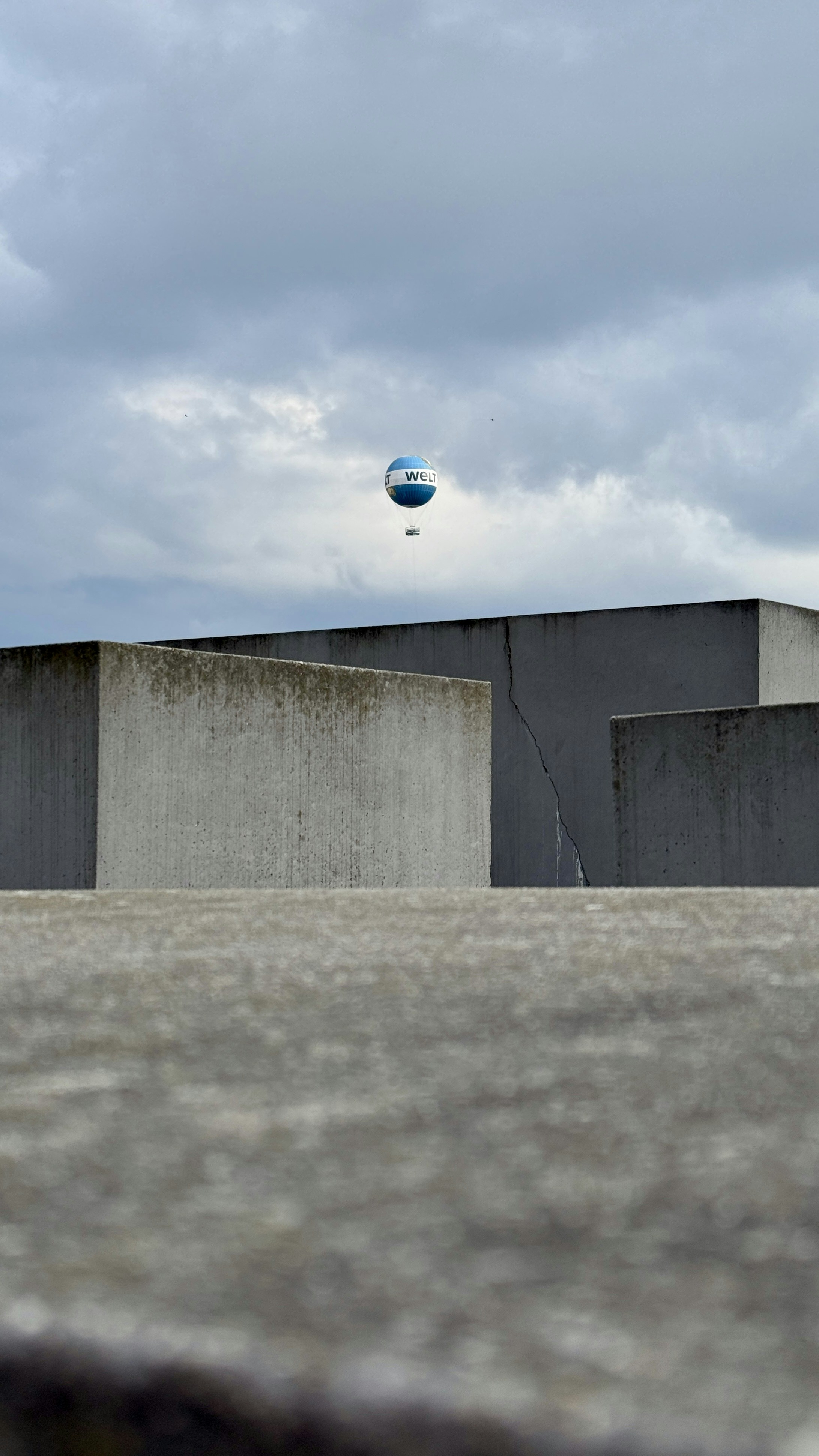A hot air balloon floats above some concrete structures. photo – Free ...