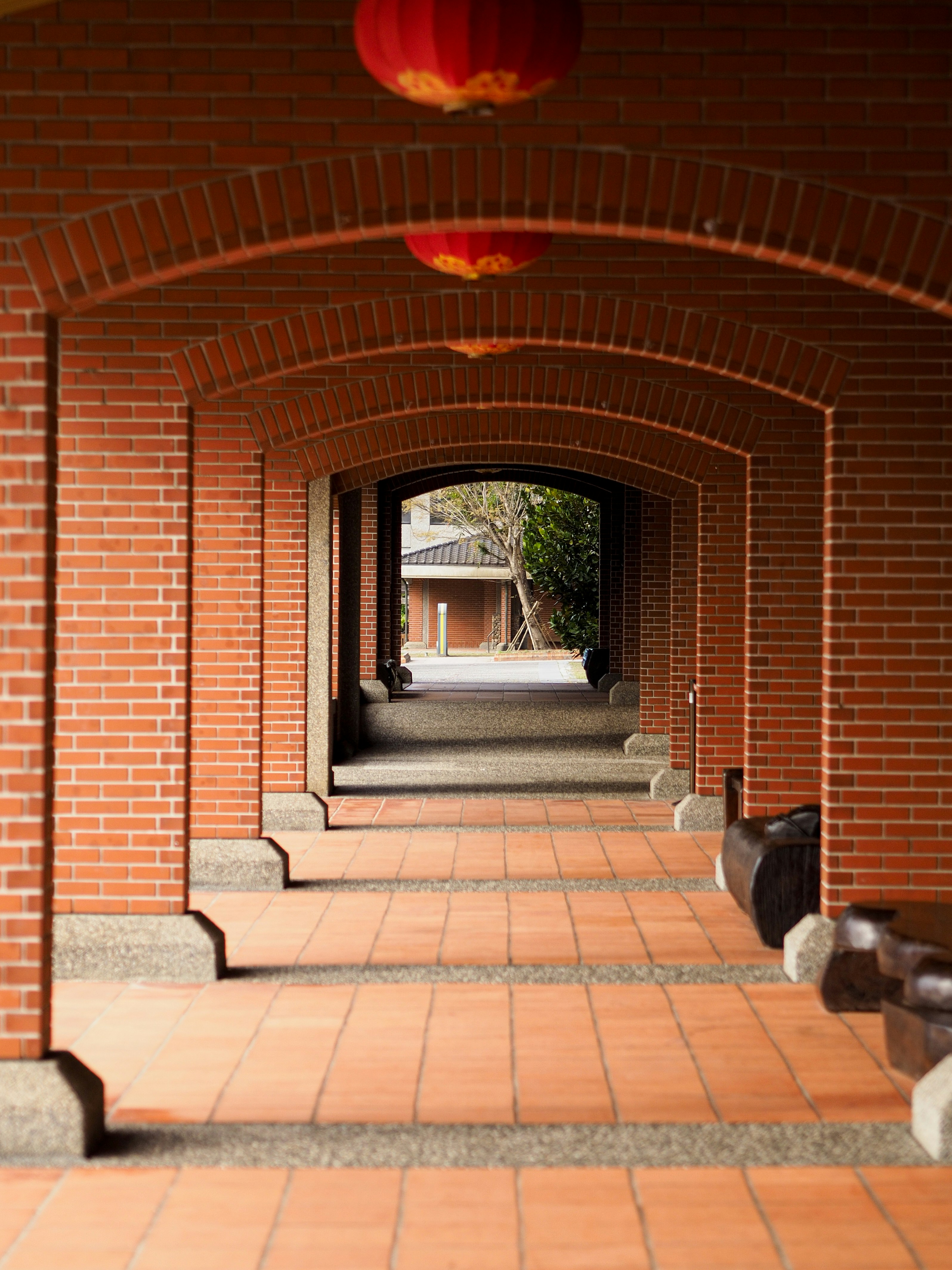 Archways to Quiet Light: Lantern-Lined Brick Corridor Reaching a Sunlit Courtyard