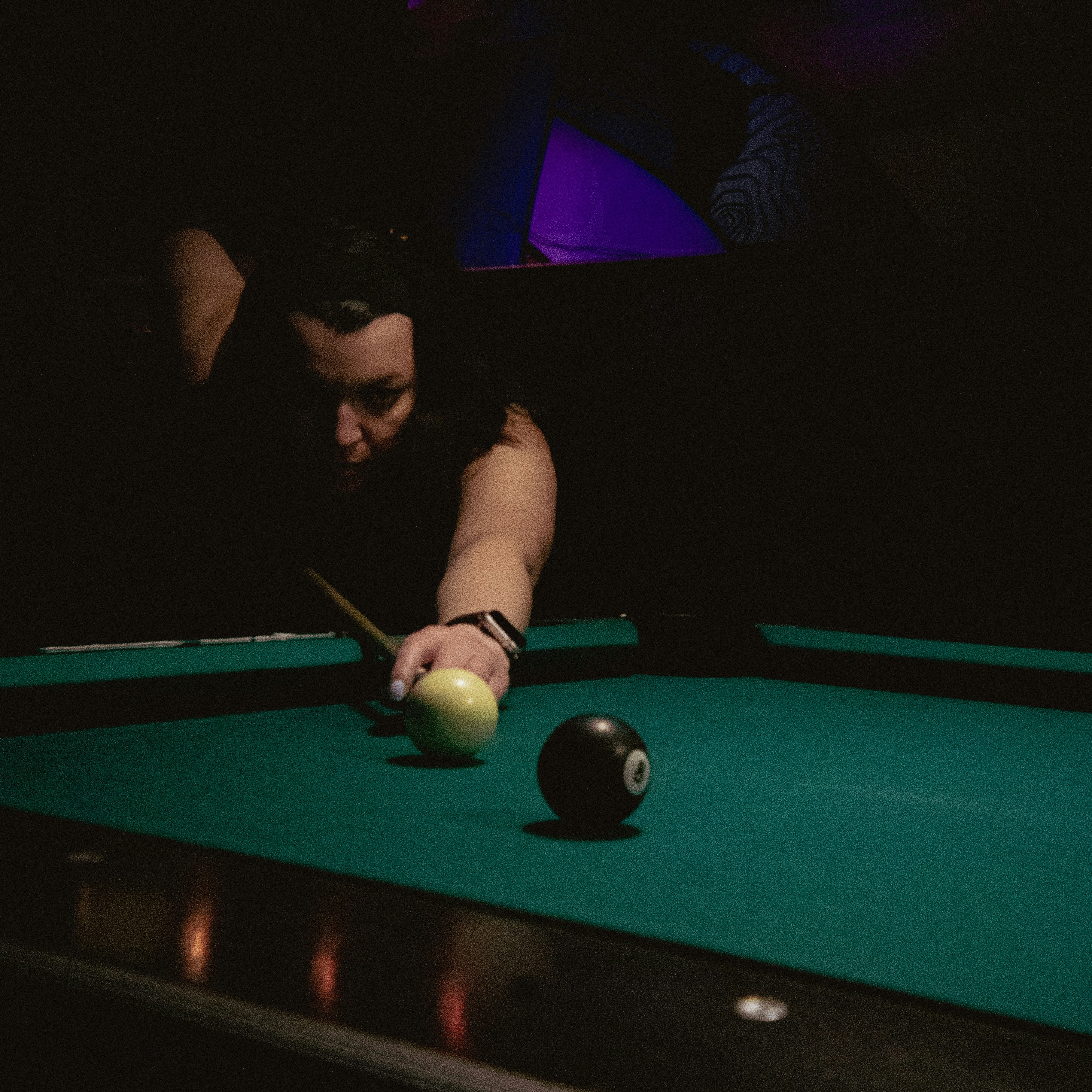 Shadowed Precision: A Pool Shot Under Purple Glow