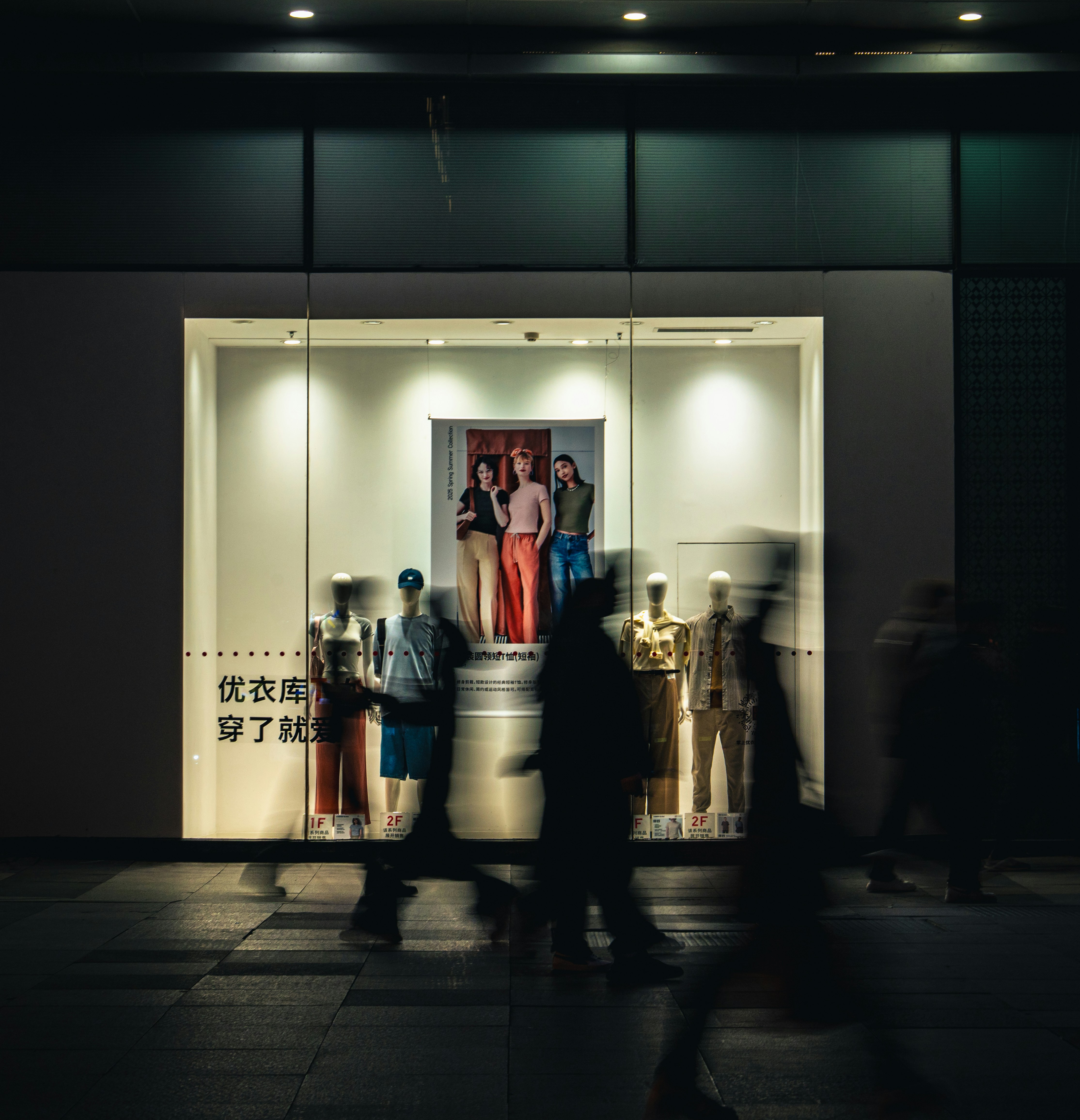 People walk past a brightly lit storefront at night. photo – Free ...