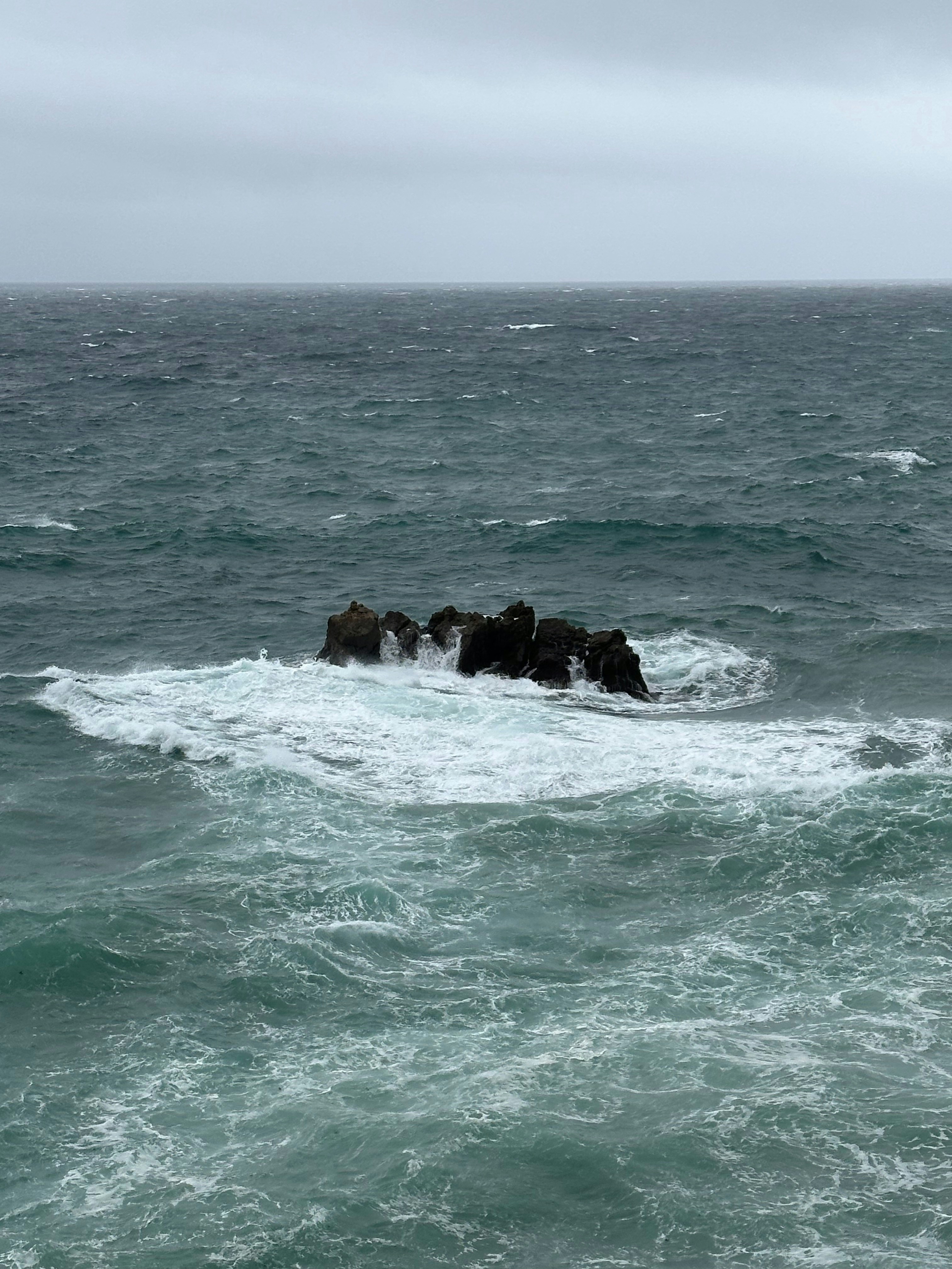 Las olas rompen alrededor de una isla rocosa en aguas tormentosas. foto ...