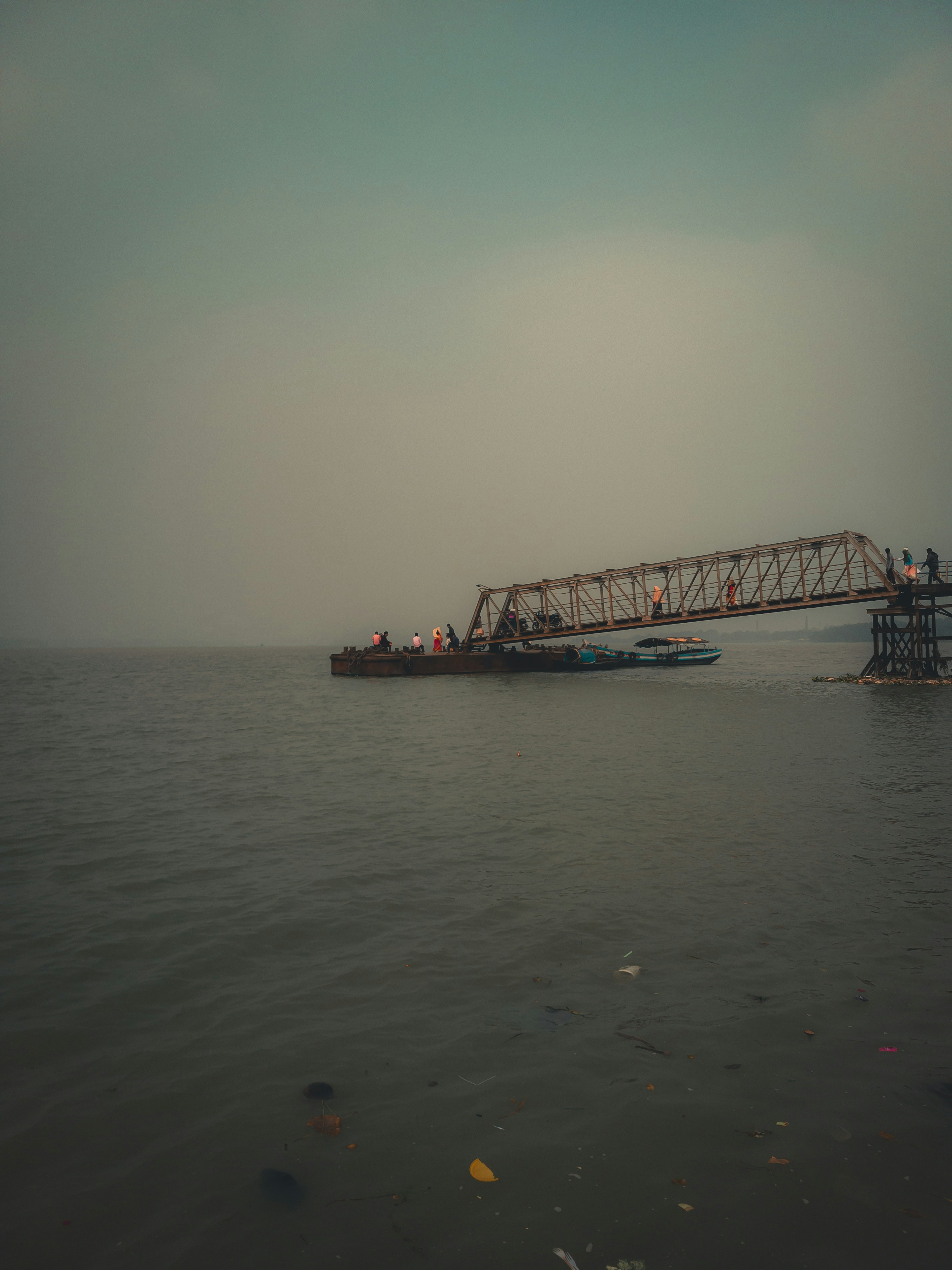 A rusty bridge spans a murky river. photo – Free Human Image on Unsplash