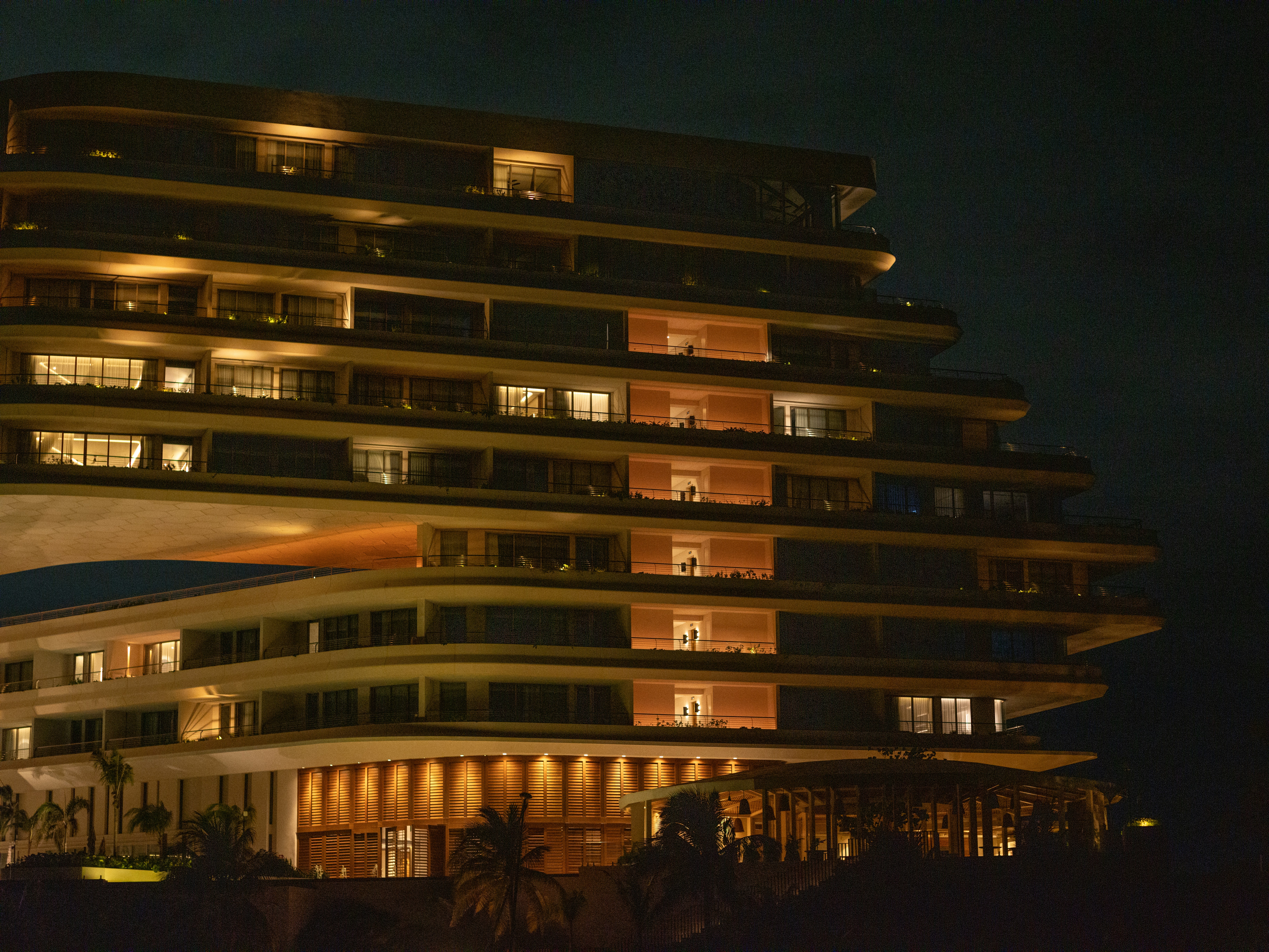 Contemporary building with curved balconies illuminated against a night sky.