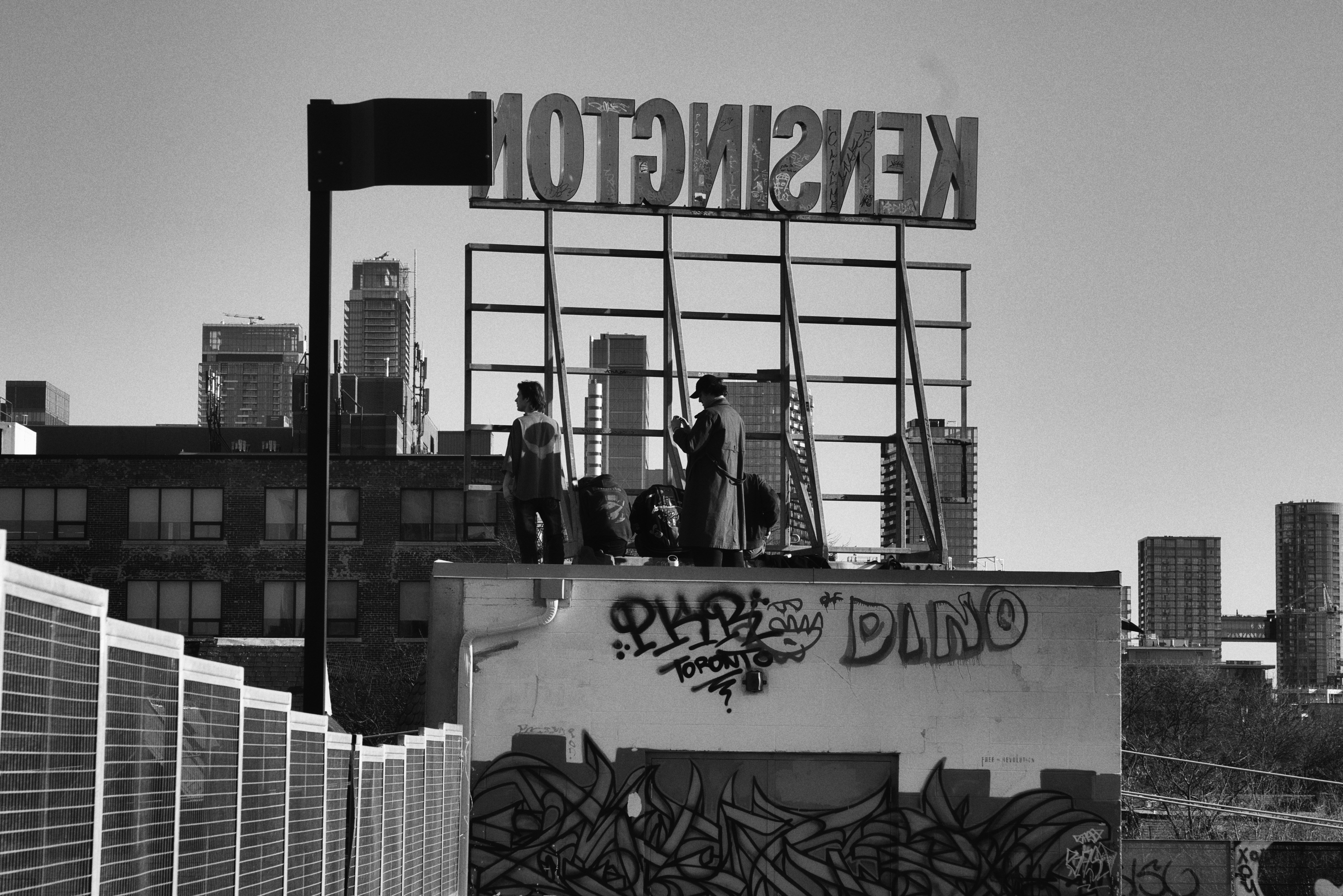 People stand on a rooftop in front of kensington. photo – Free City ...