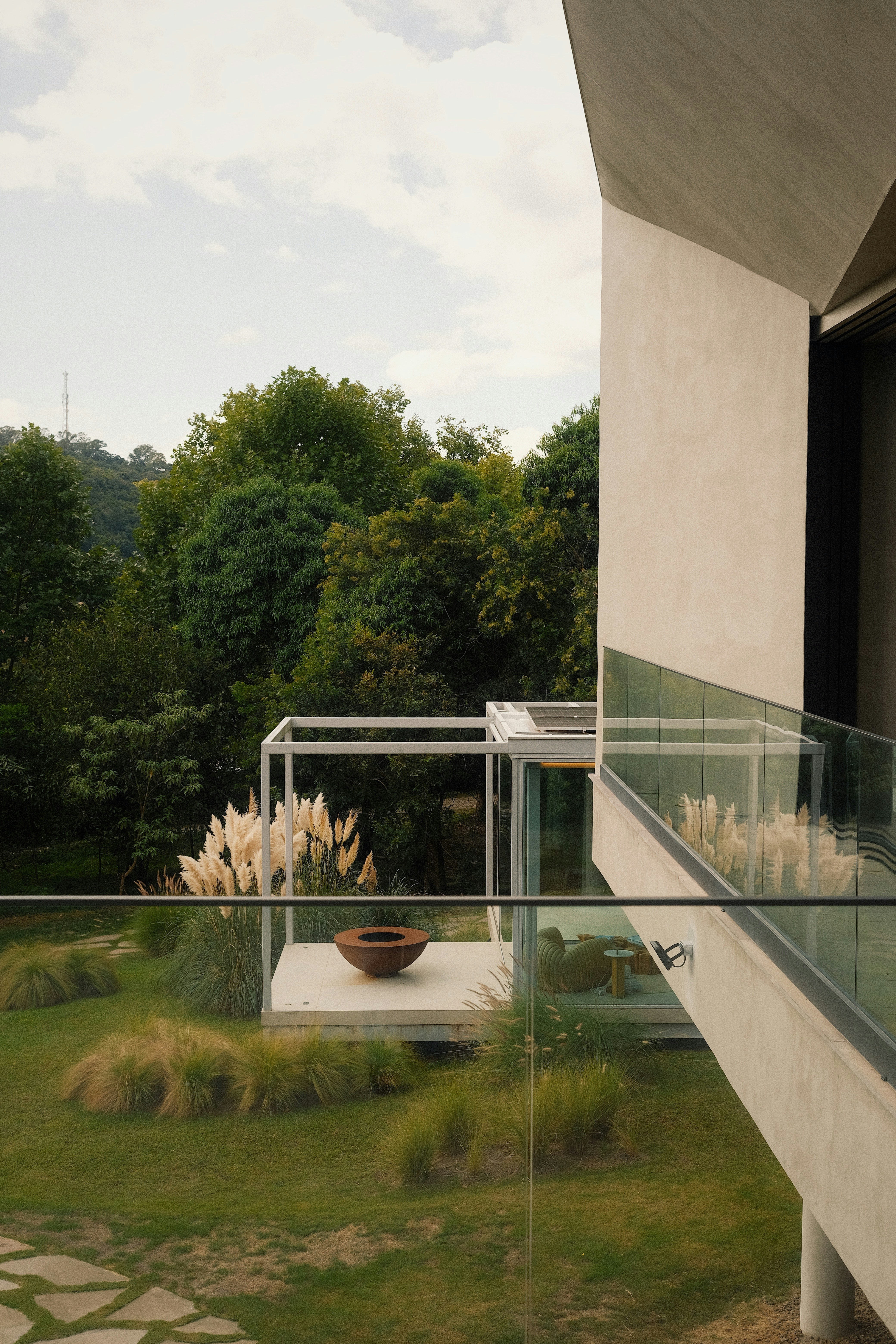 Contemporary architectural structure overlooking a lush garden with a distant view of the forest.