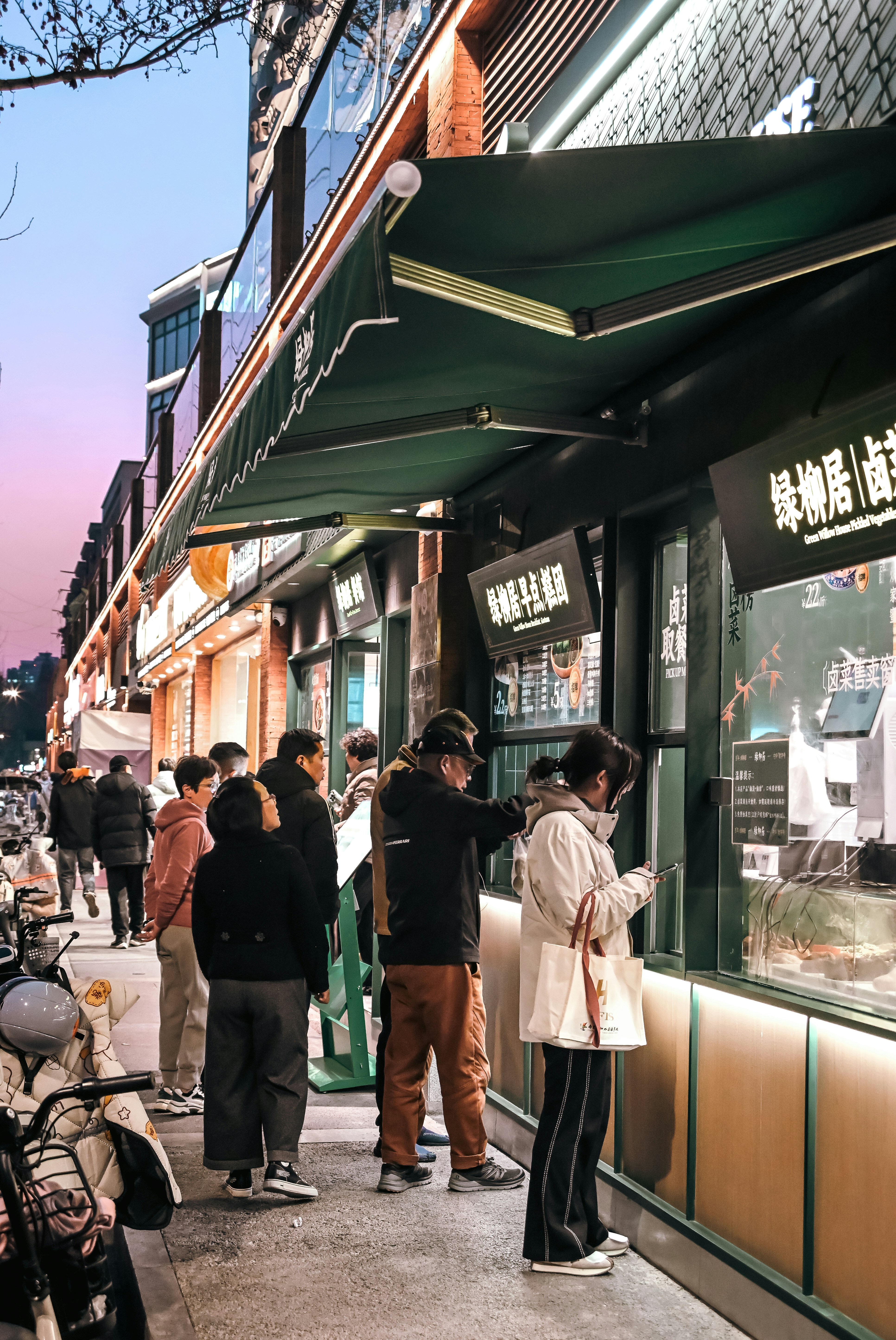 Under Green Awnings at Dusk: A Street-Food Queue Along a Neon-Tinted Lane