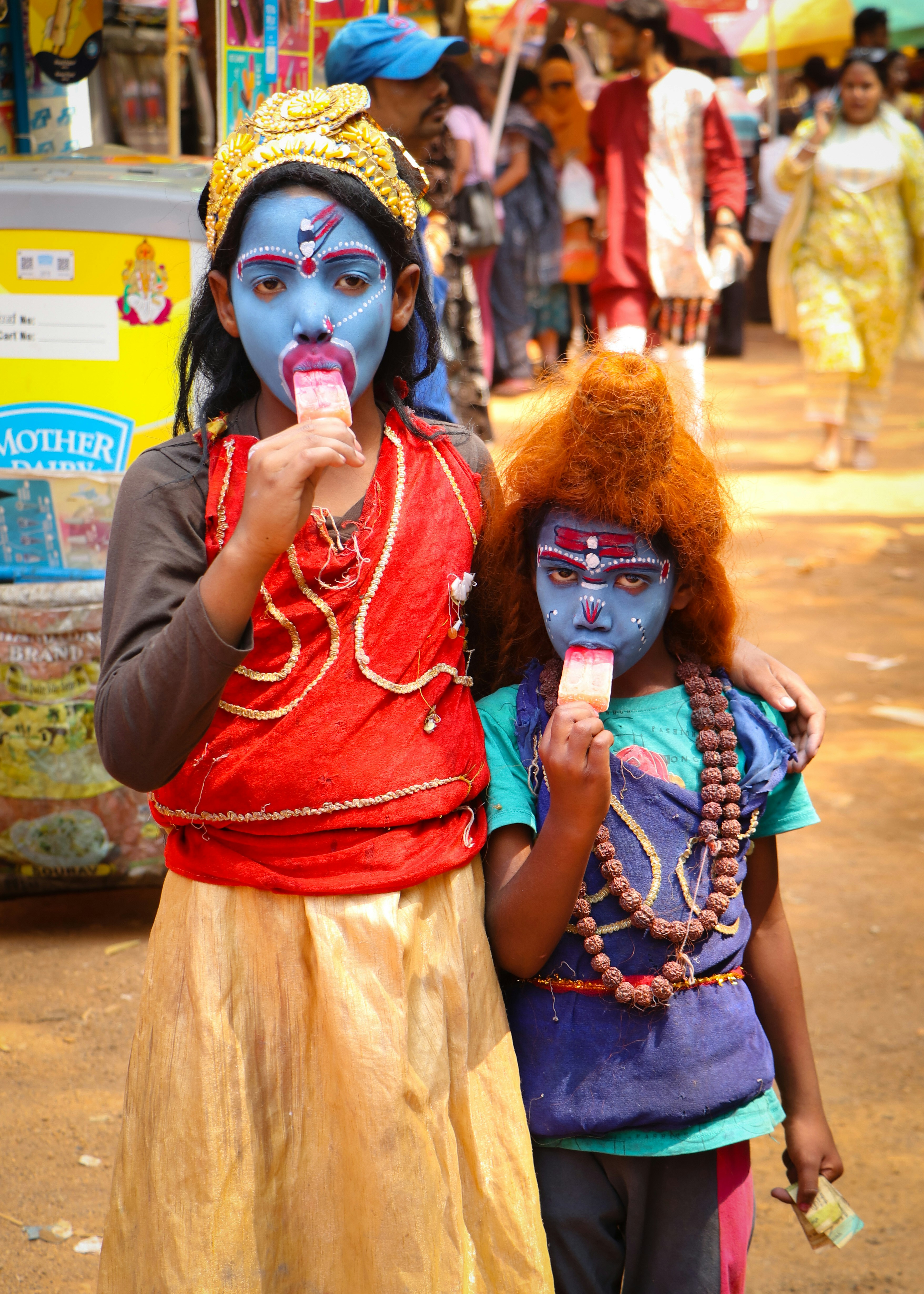 Royal Blue Masks at the Carnival: Two costumed children share a popsicle