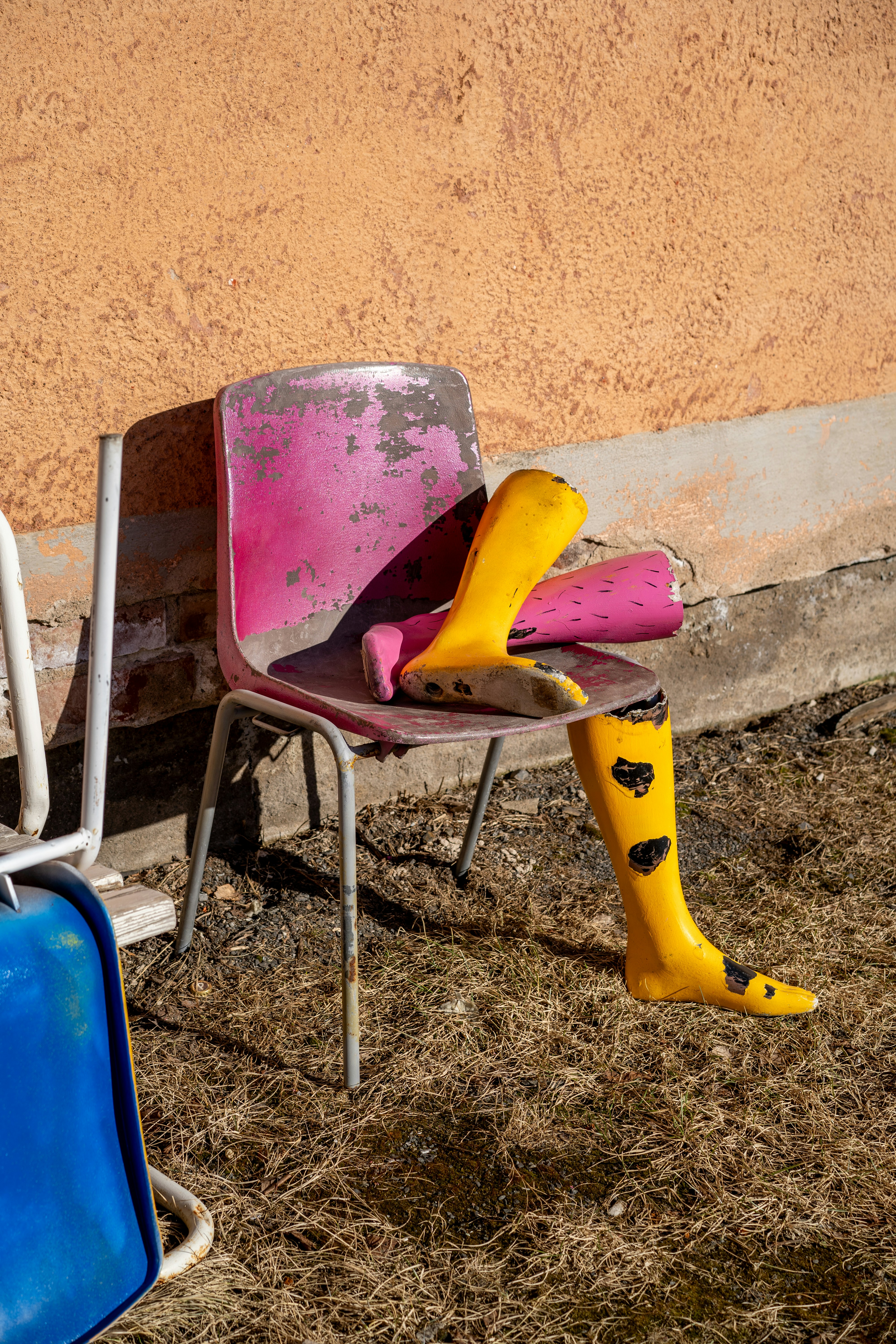 Pink Chair with a Bright Yellow Leg Against a Sunlit Wall
