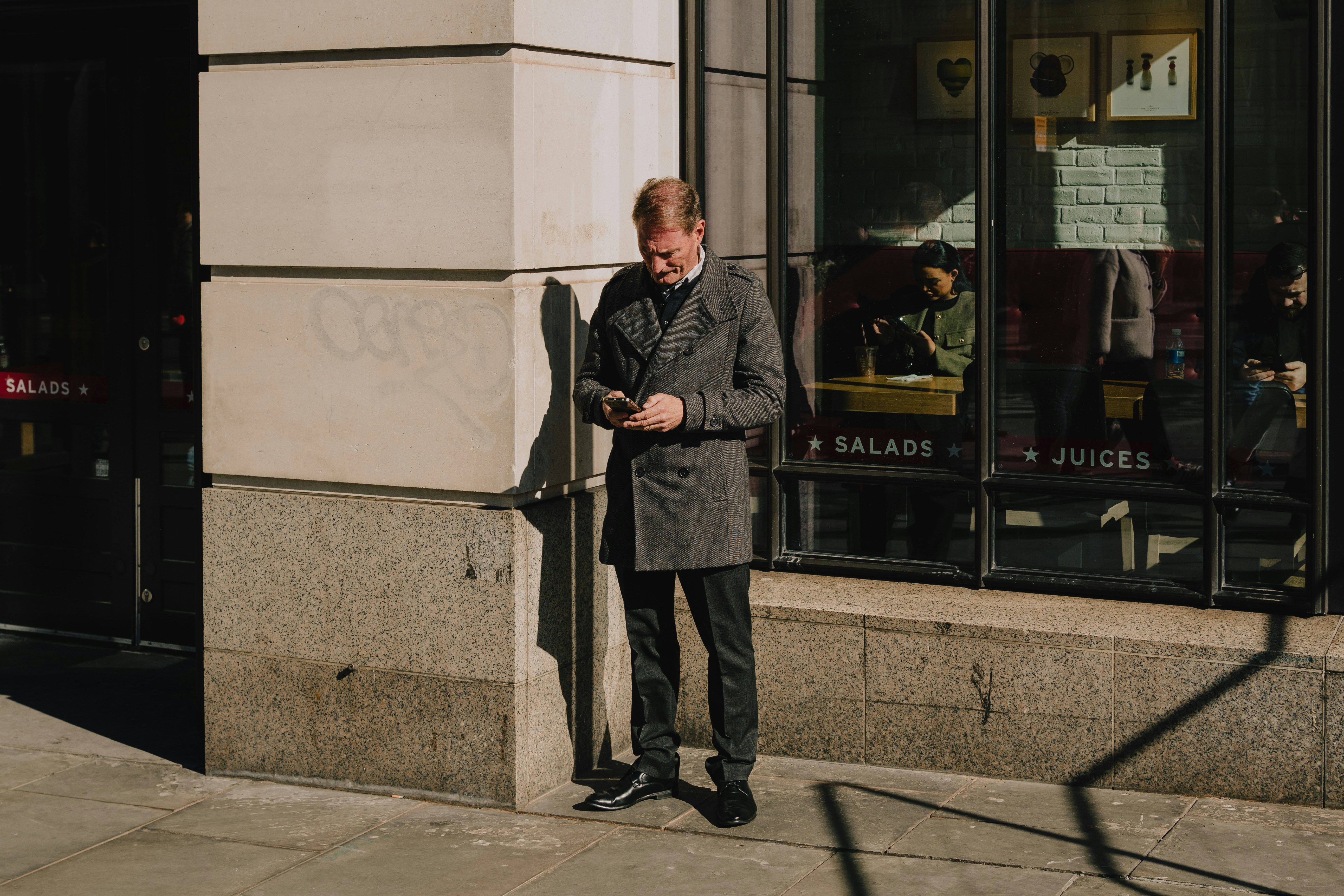 Midday Contemplation by the Storefront: A Man in a Grey Overcoat