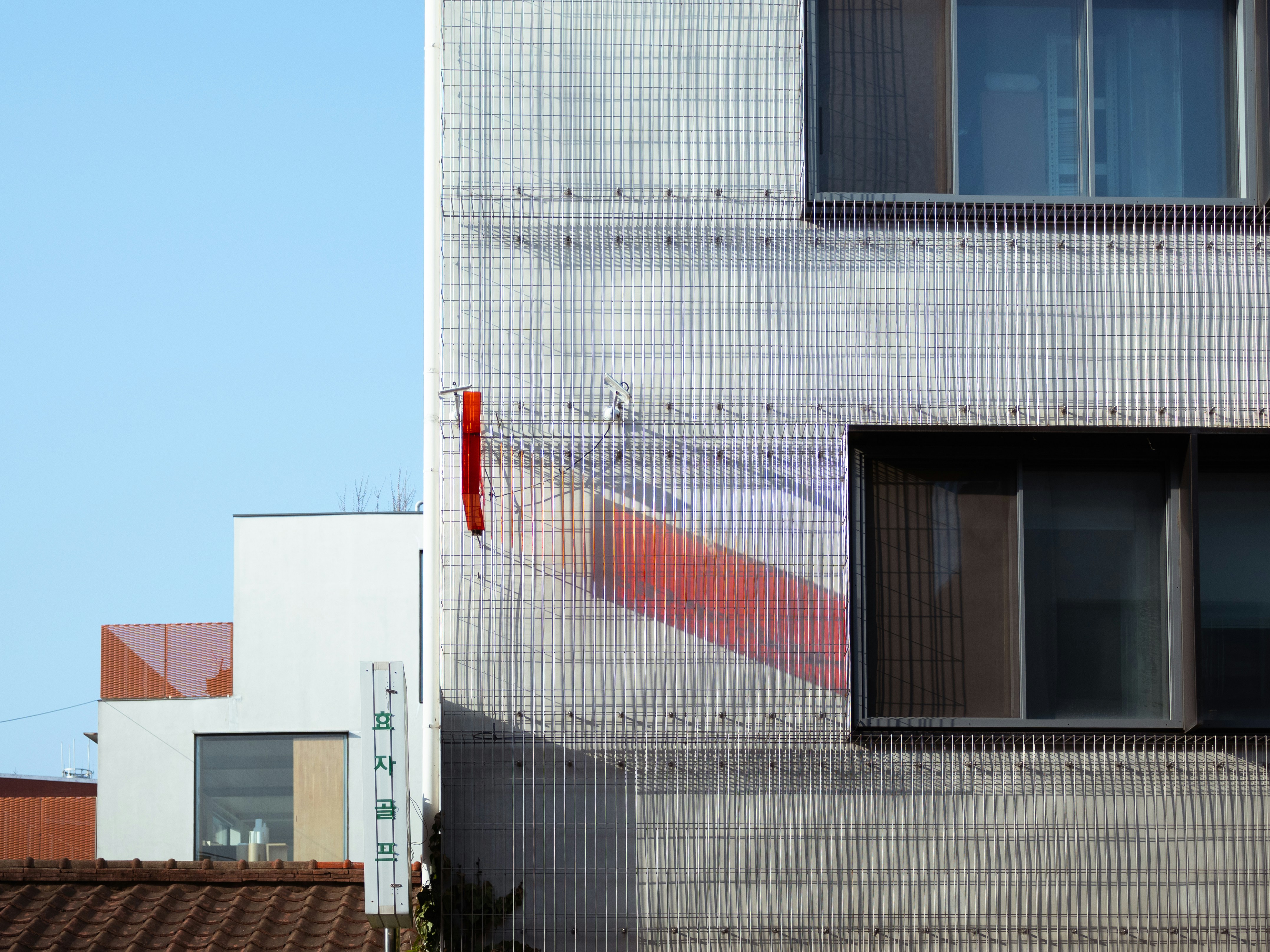 Red Slender Banner Adrift Against a Grid-Tiled Facade
