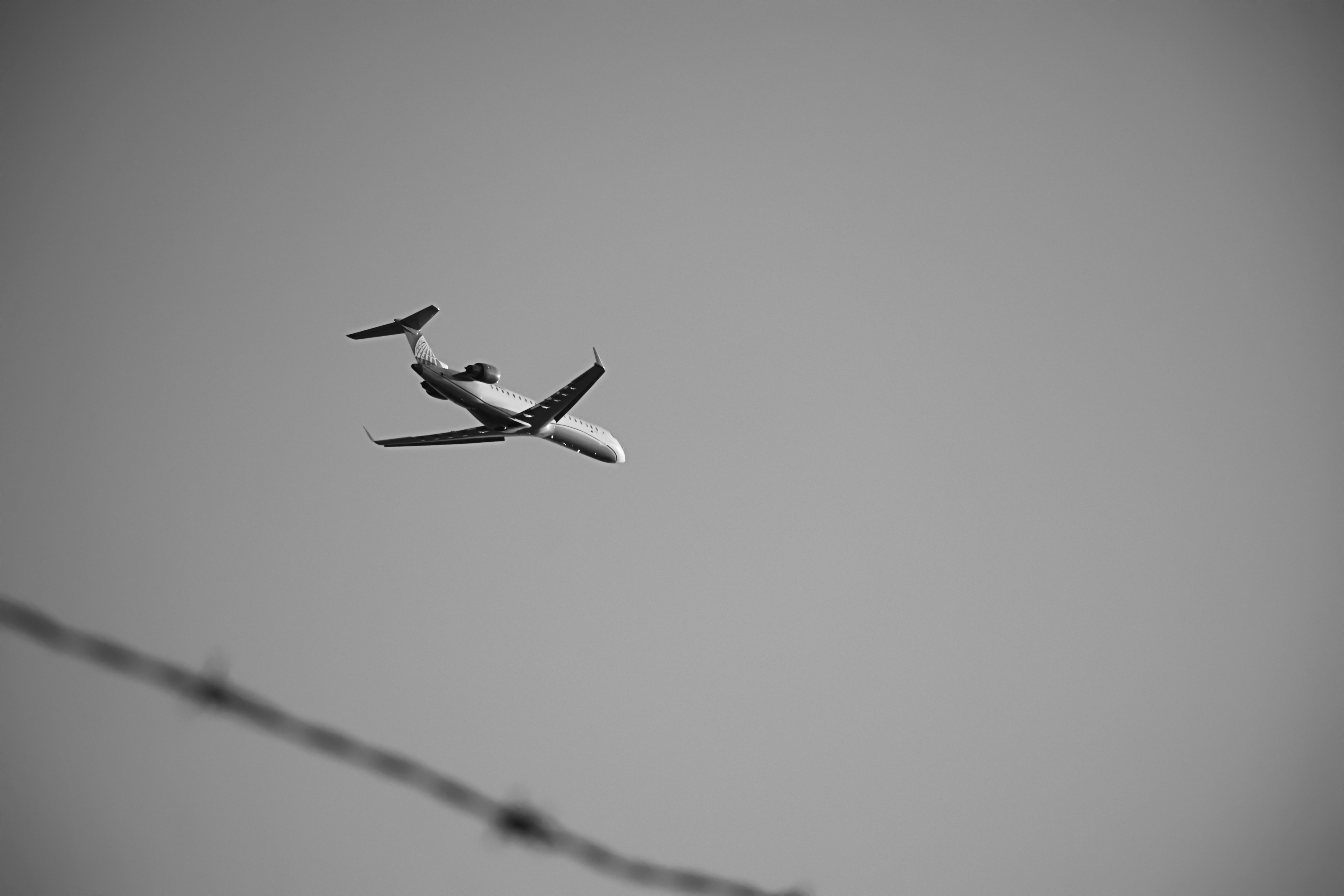 An airplane flies high in the clear sky.