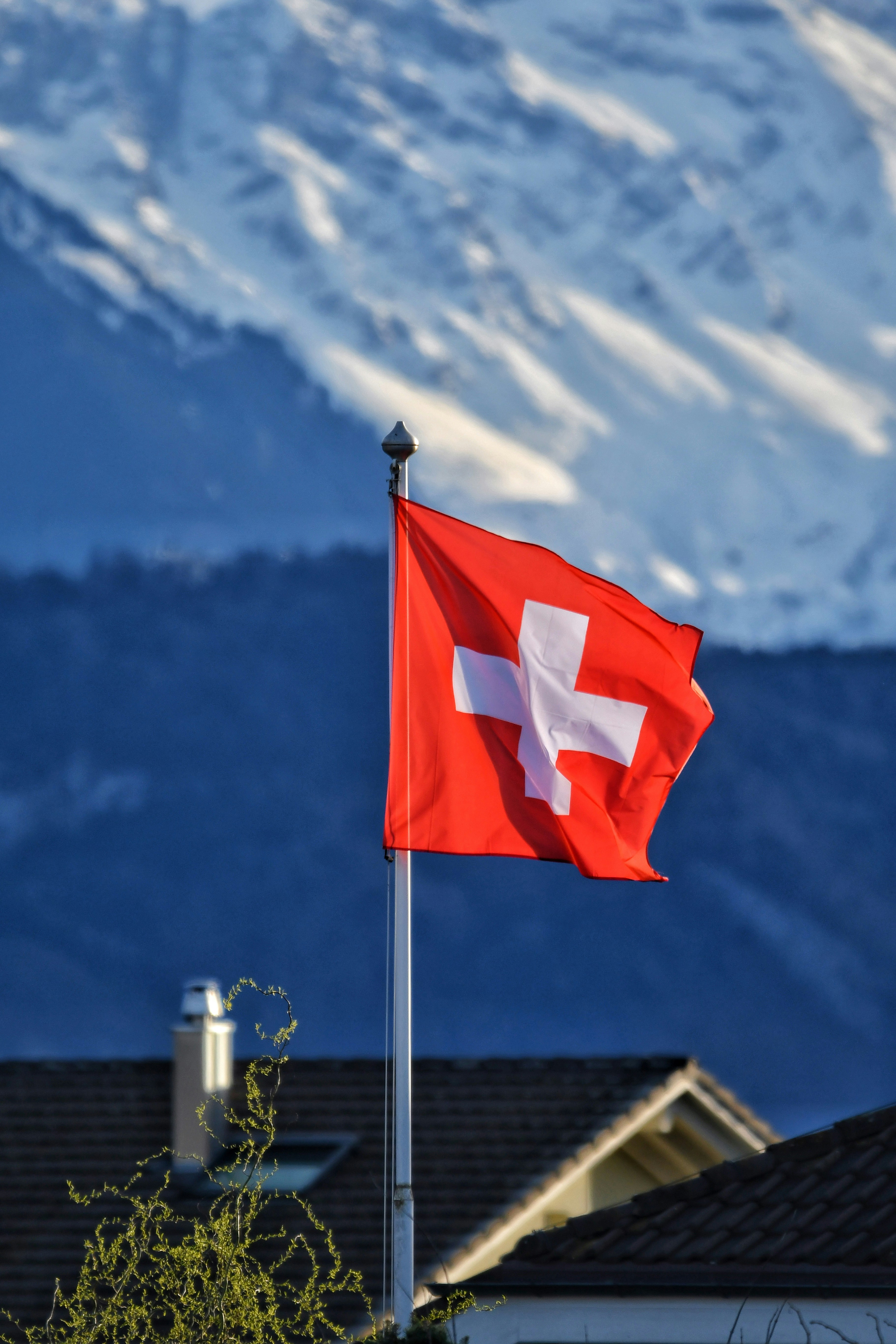 Swiss Flag Emblem Rising Over Alpine Rooftops