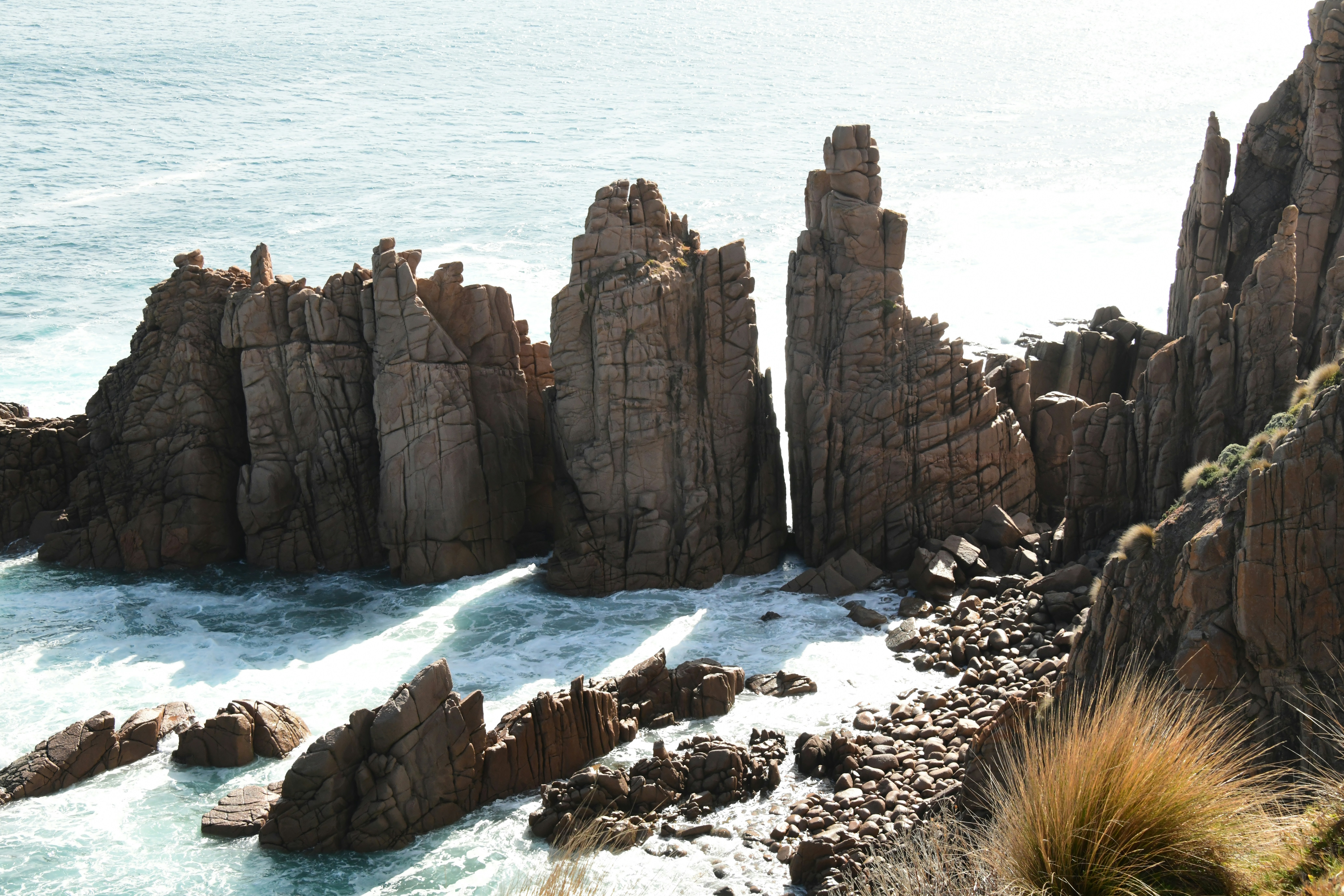 Jagged rocks border a foamy ocean. photo – Free Beach Image on Unsplash