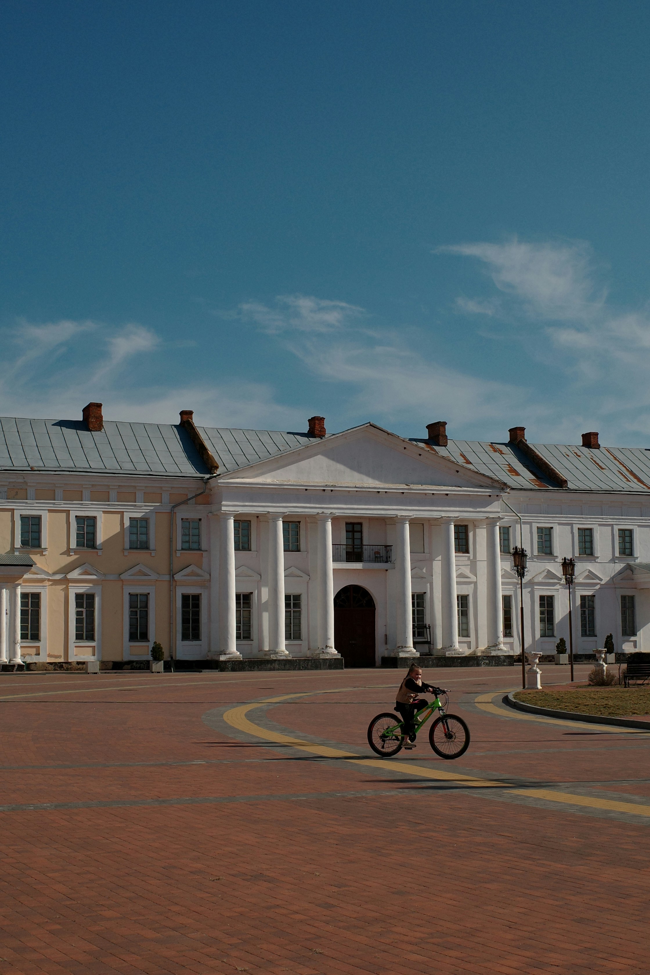 Green Bicycle Crossing the Neoclassical Plaza under a Clear Blue Sky