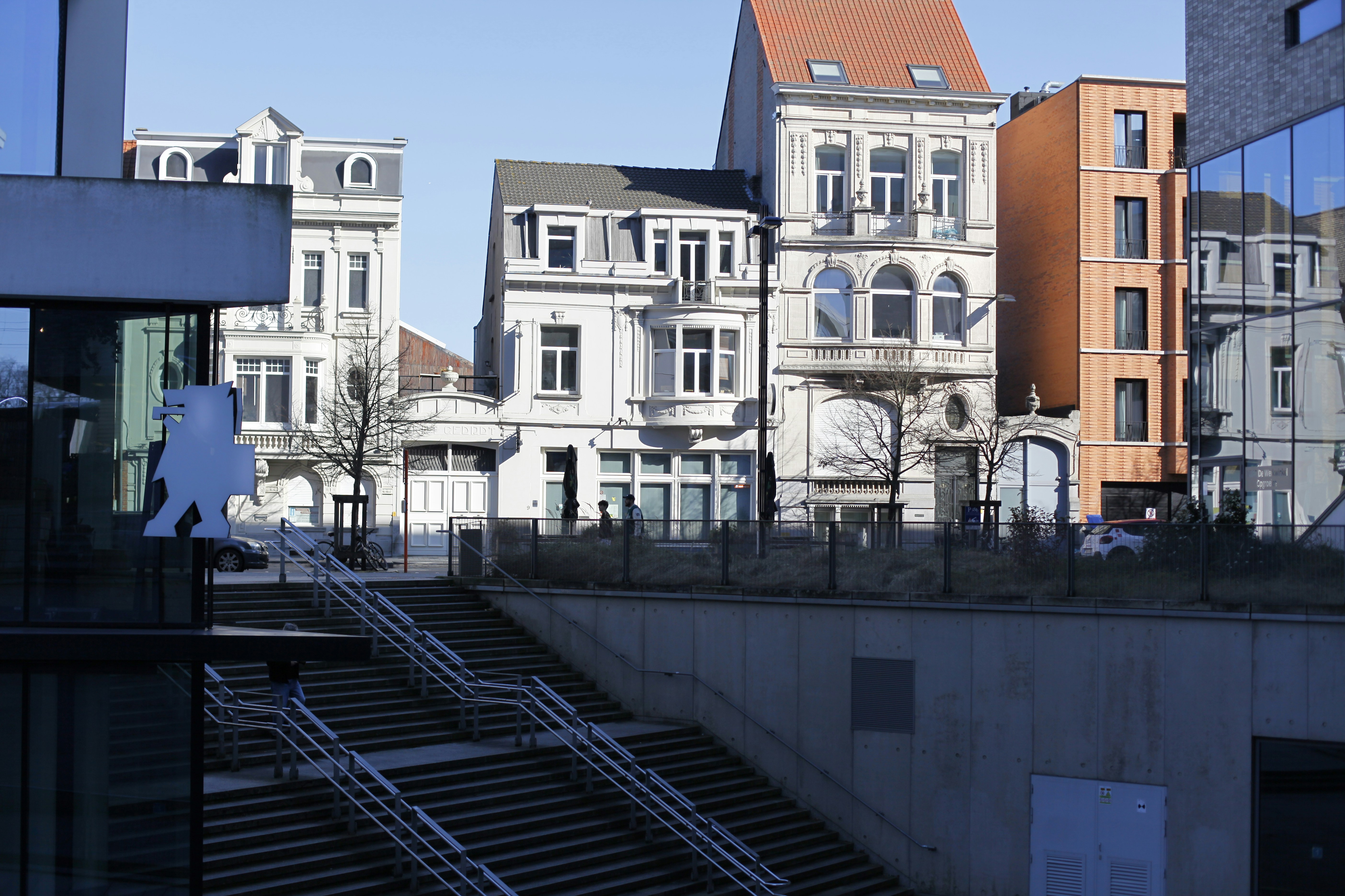 Modern and historic buildings reflect in urban glass under clear blue sky.