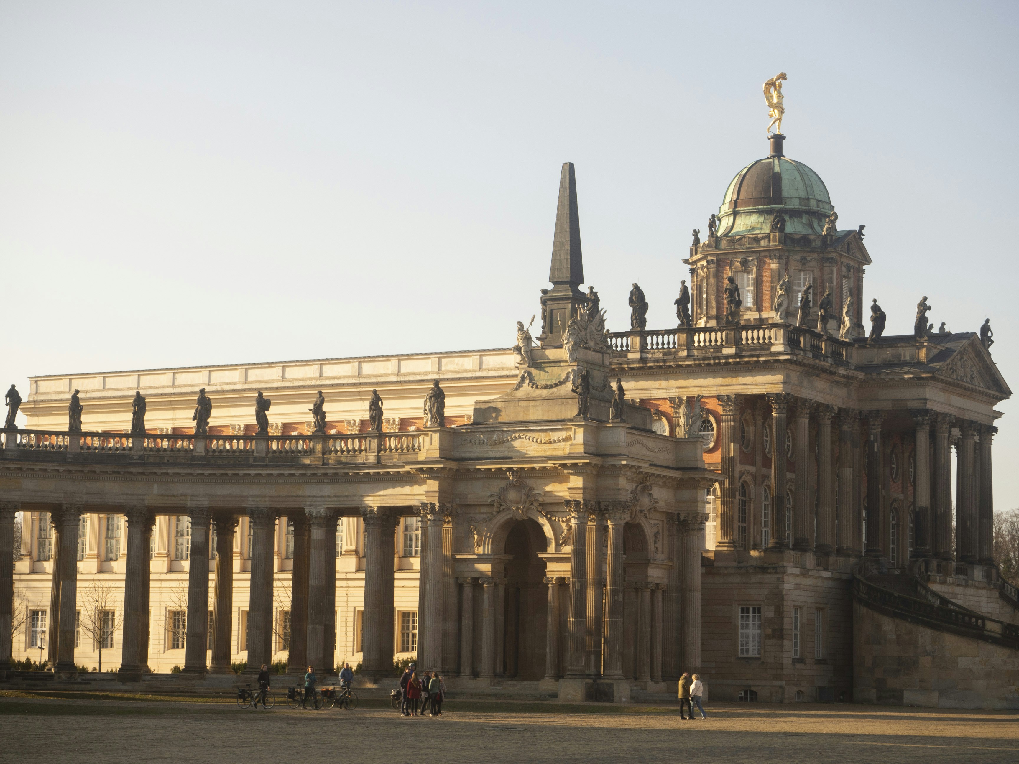 Historic building with ornate statues and a domed roof bathed in warm sunlight.