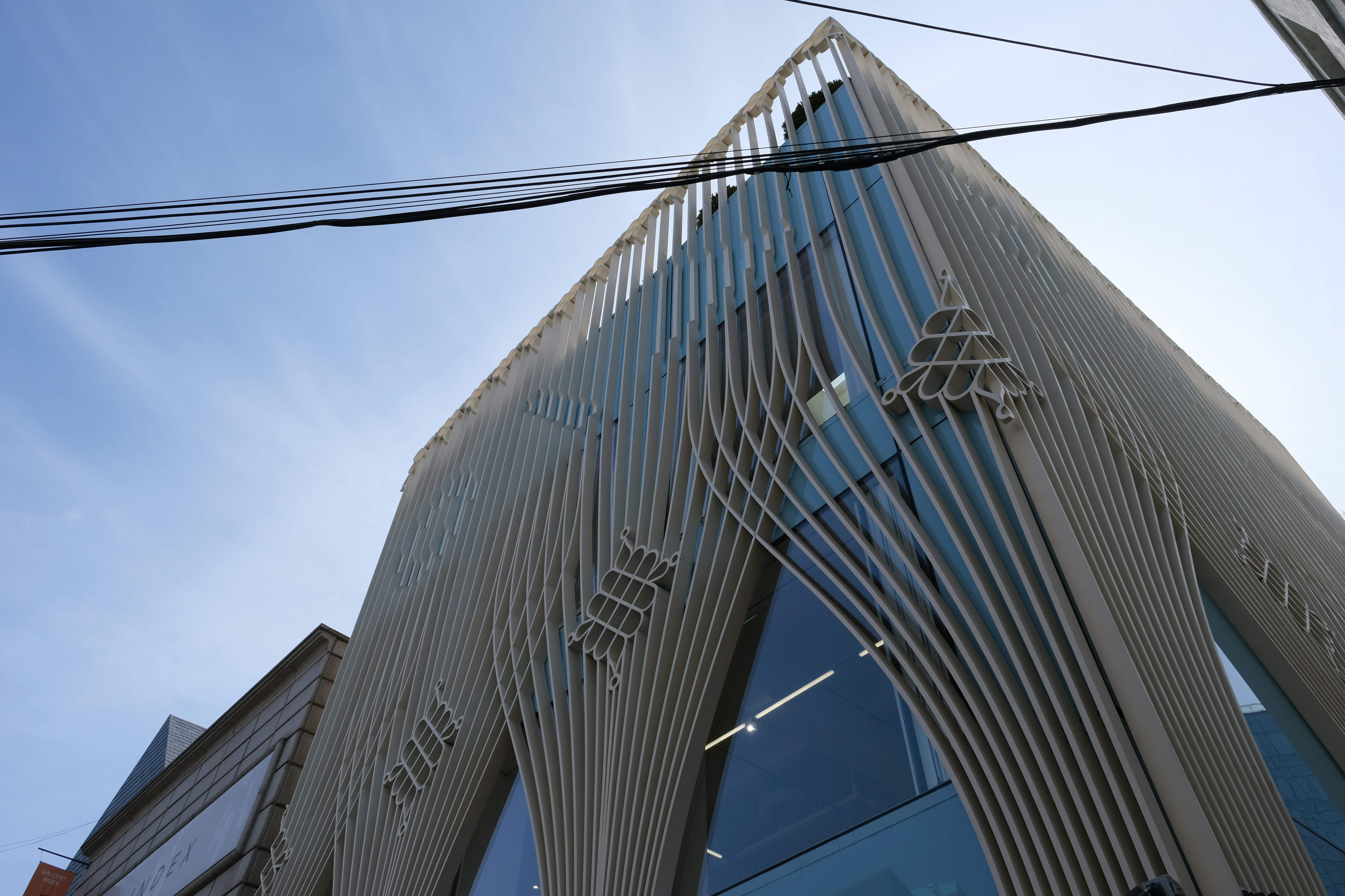 Contemporary building facade with curved, vertical lines against a clear sky.