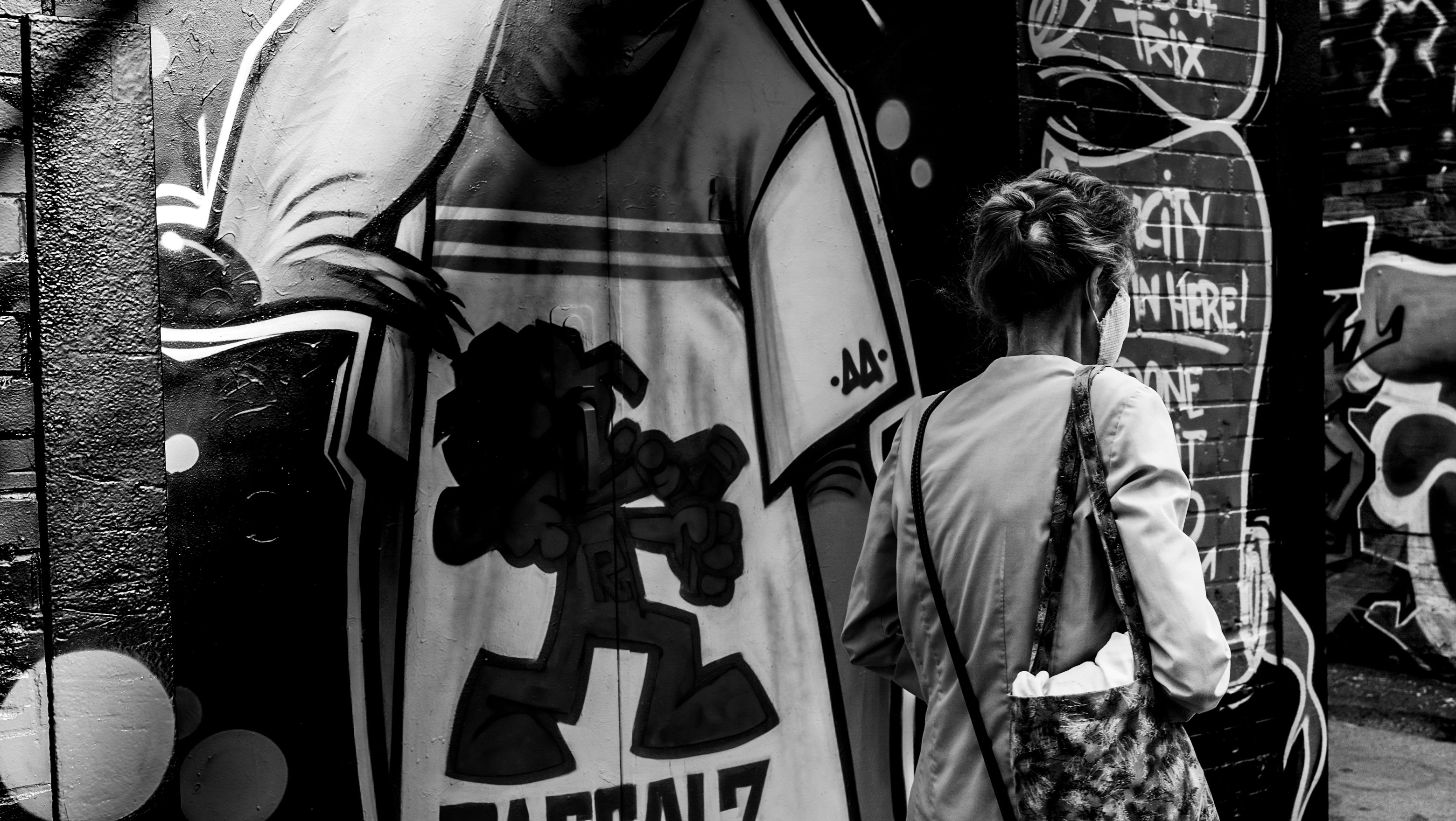 Black and white street art with a person walking past vibrant graffiti walls.