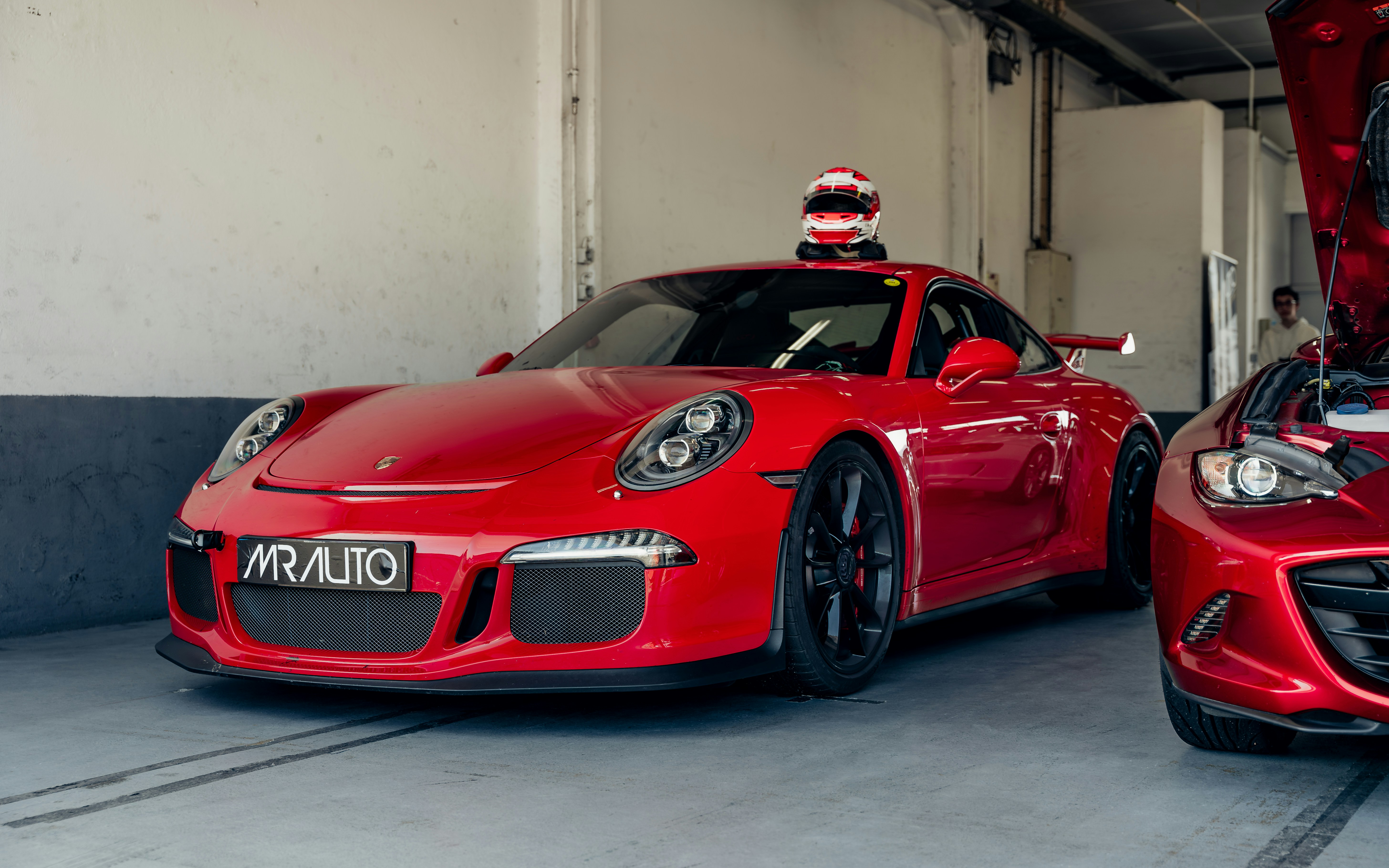 Une Porsche rouge et une Mazda sont garées dans un garage. photo ...