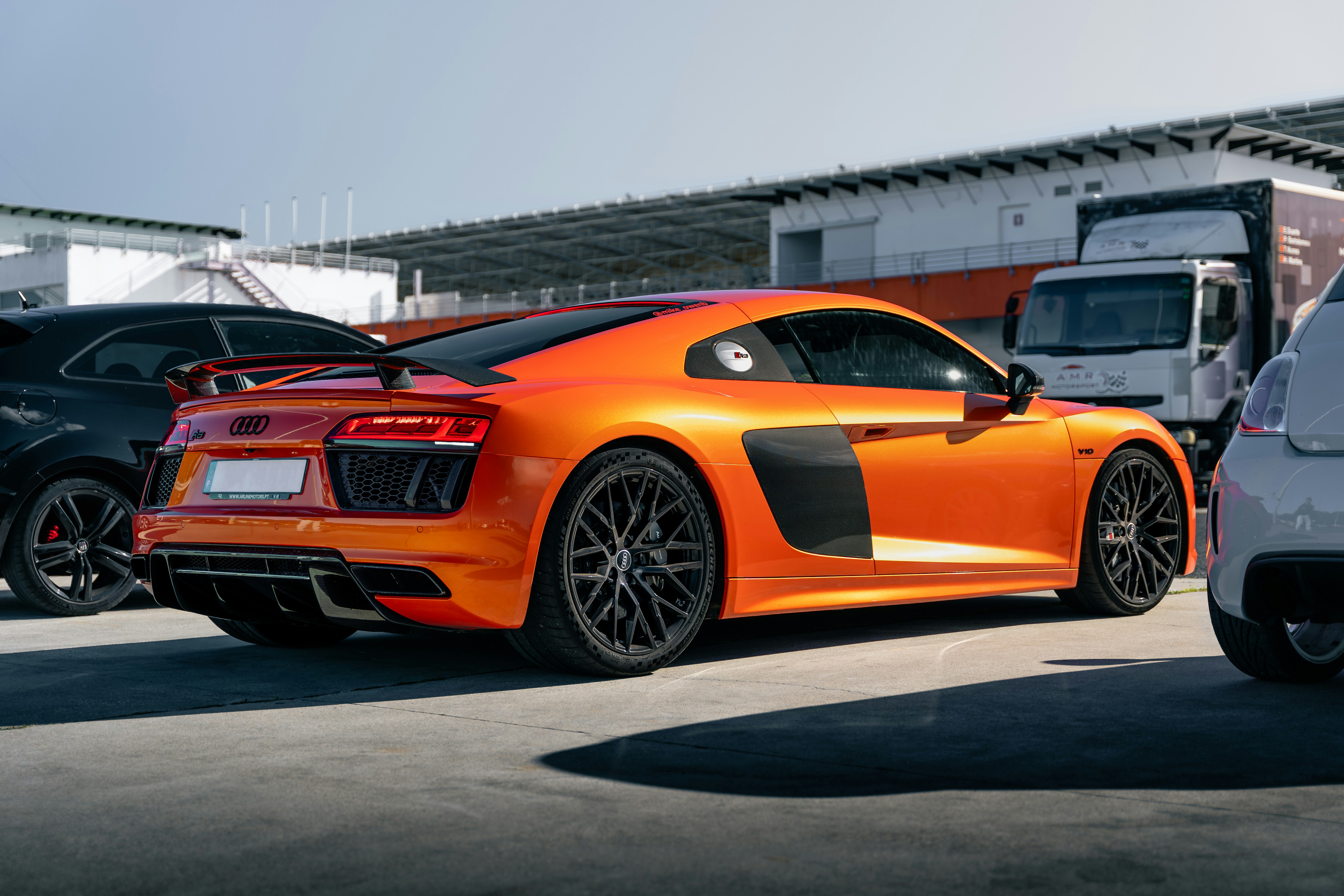 An orange audi r8 sits on a track. photo – Free Sports car Image on ...