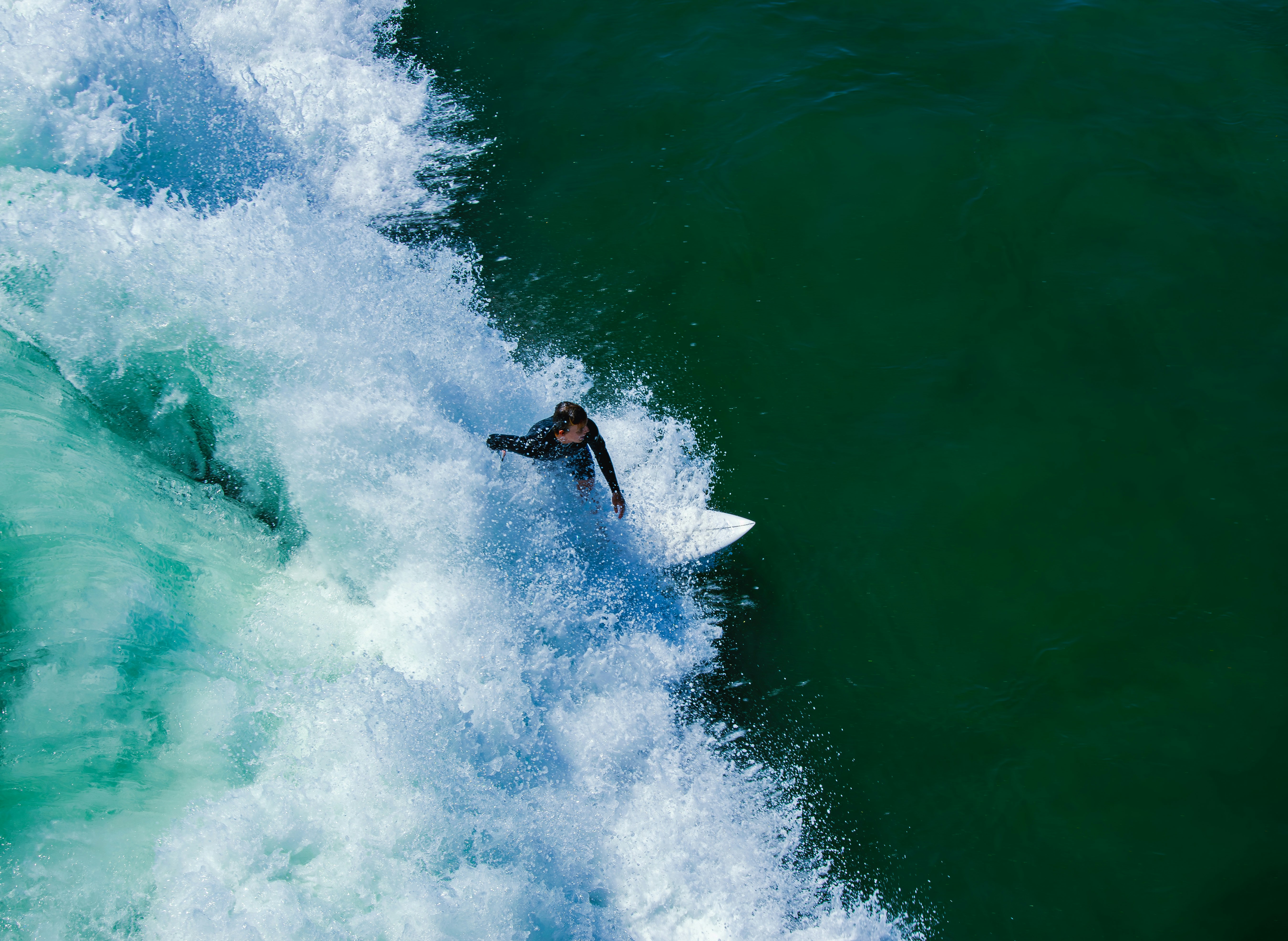 Surfer skillfully carving through a breaking wave in the ocean under clear skies.