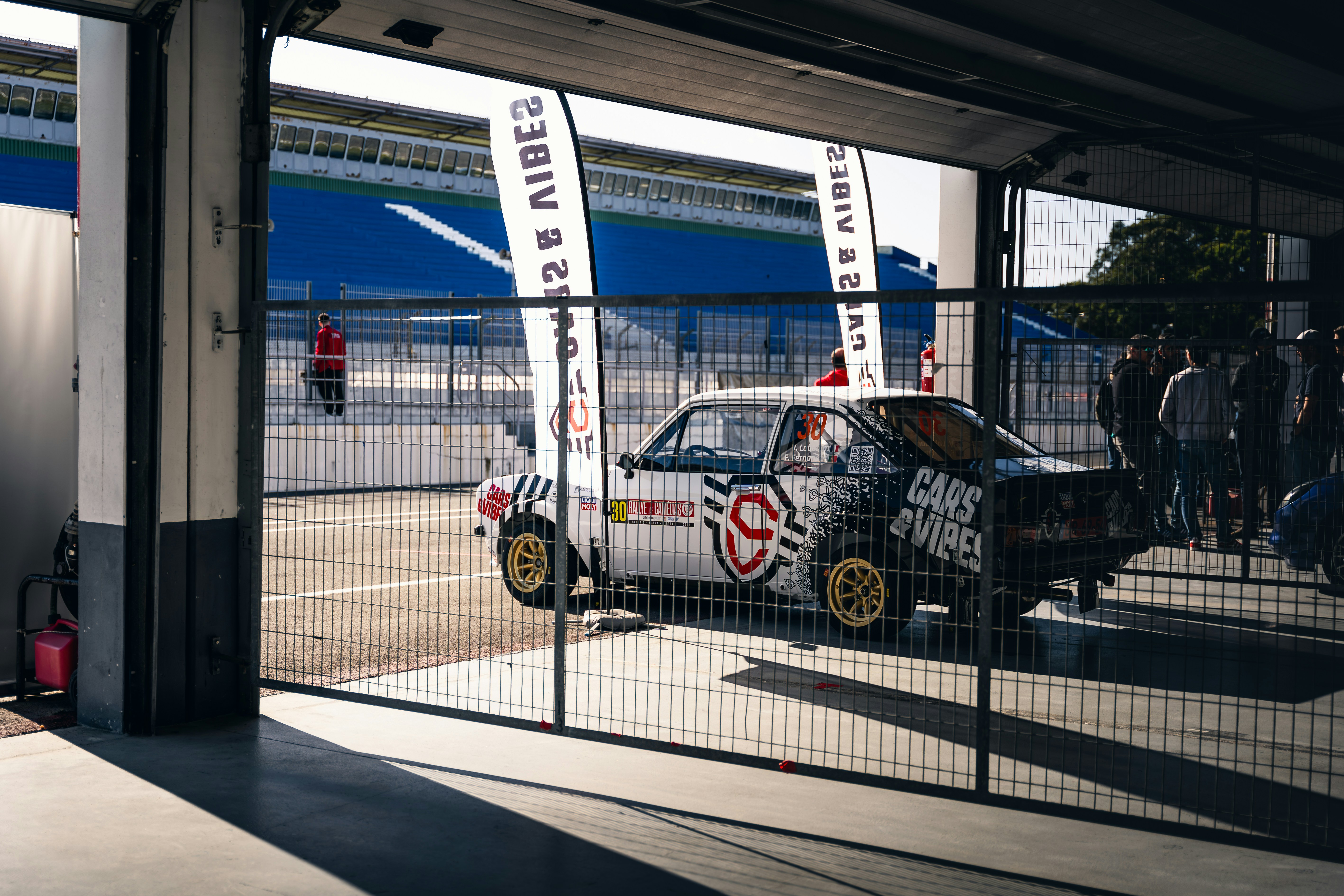 Race‑car in the pit: sunlight, shadows, and a lean tire routine