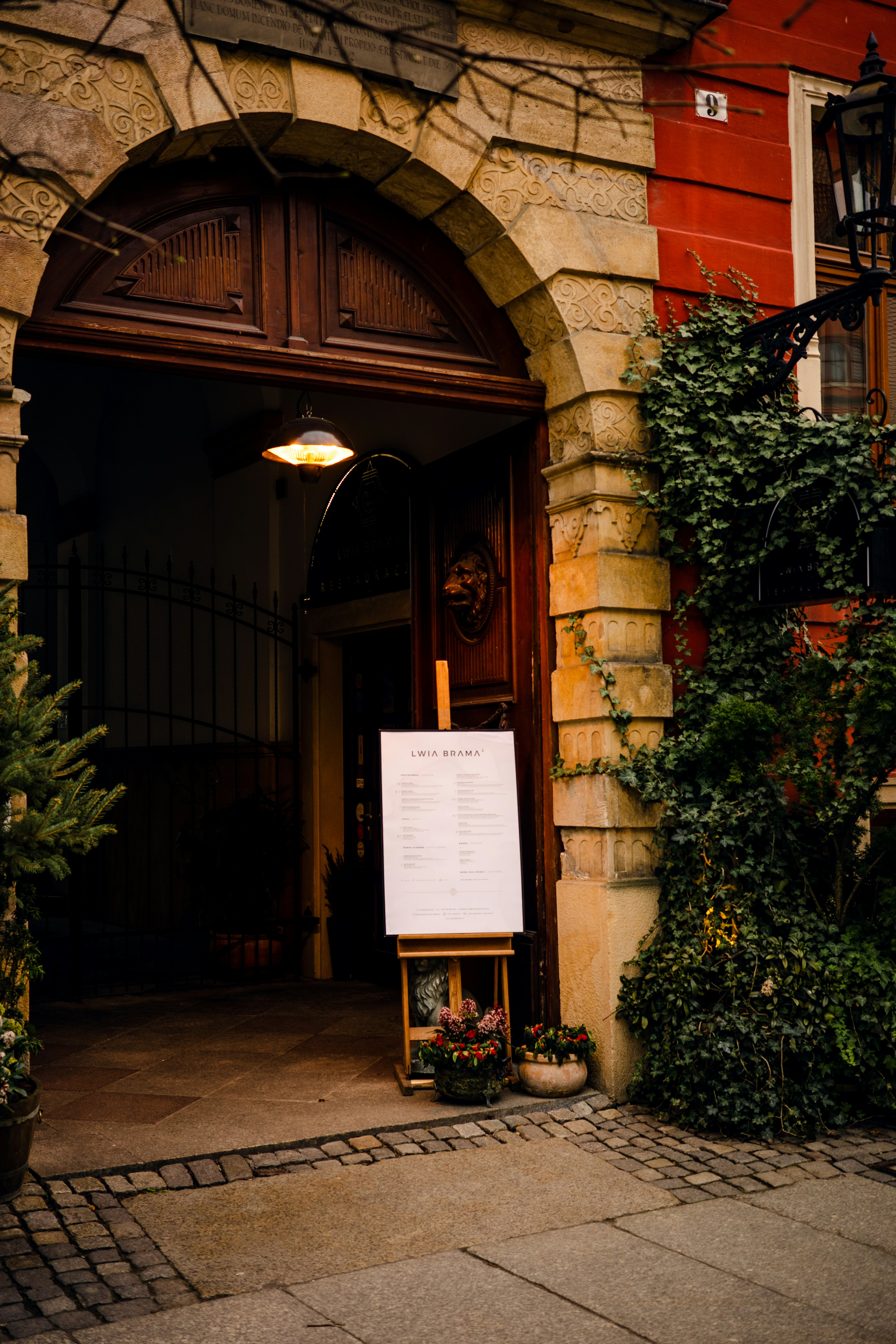Stone archway leading to an inviting doorway with a menu display and lush greenery.