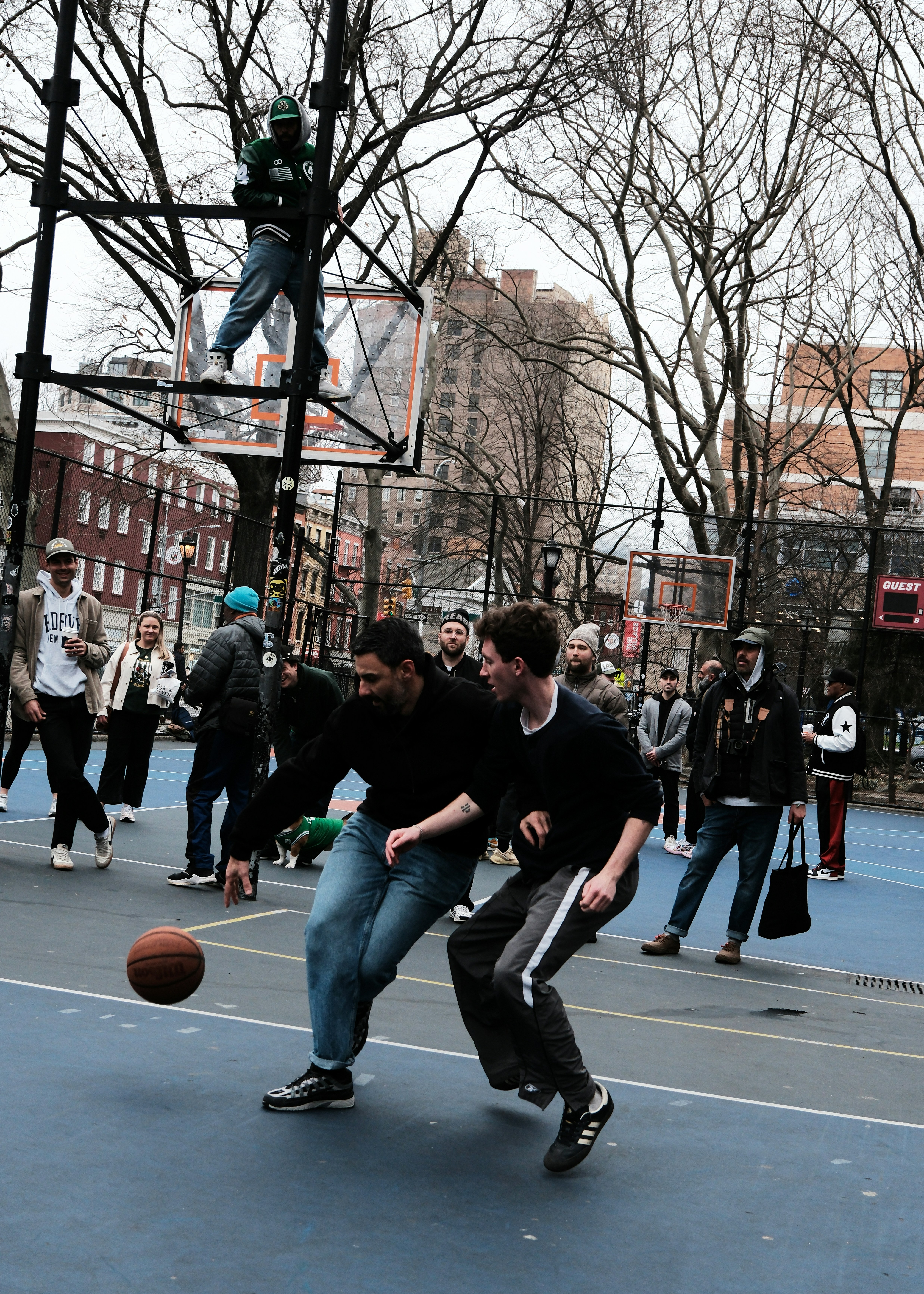 Urban Court Dash: Two Players Chase a Dribble as Spectators Rally
