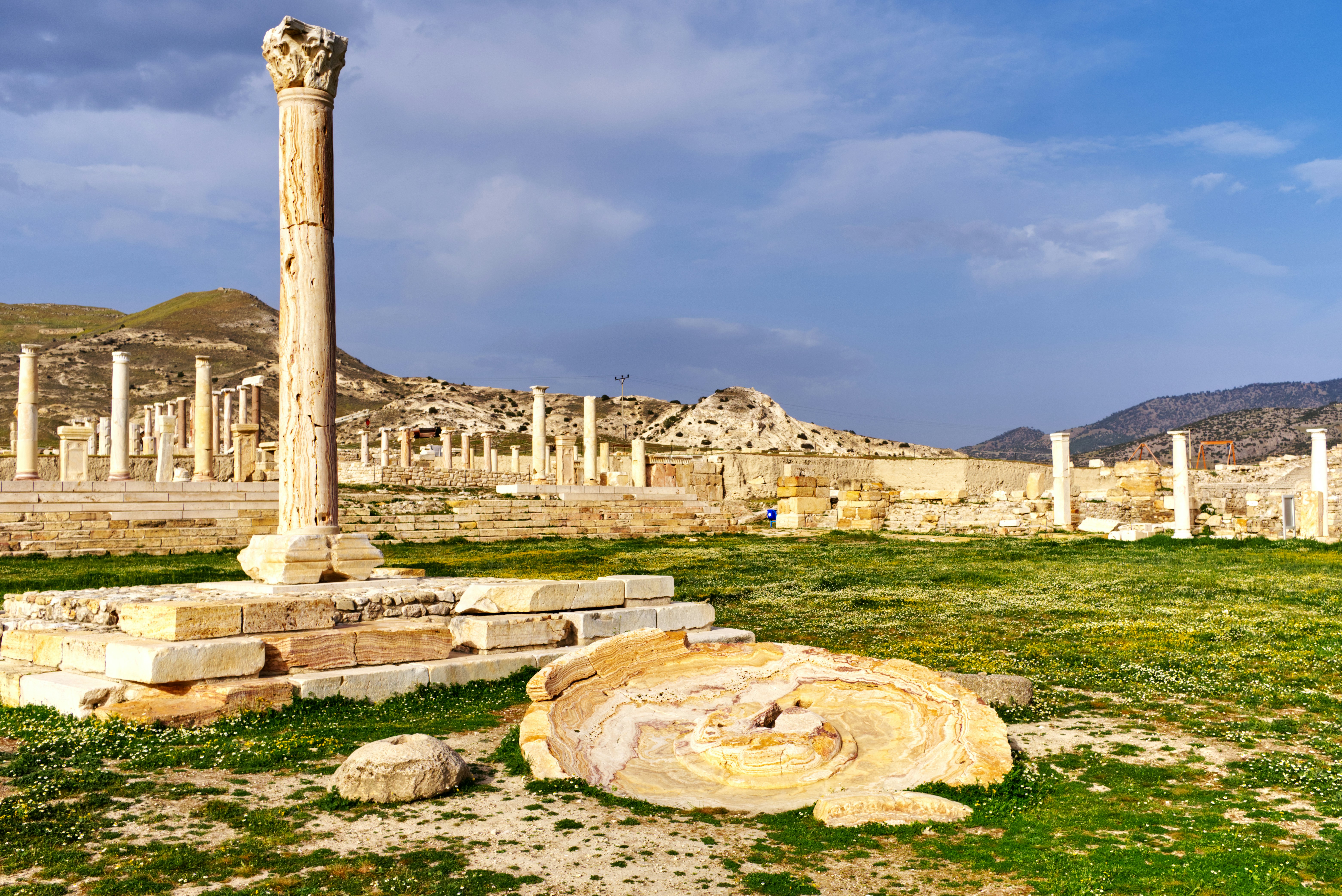 Ancient columns and ruins under a bright blue sky at the historic site of Tripolis in Turkey.