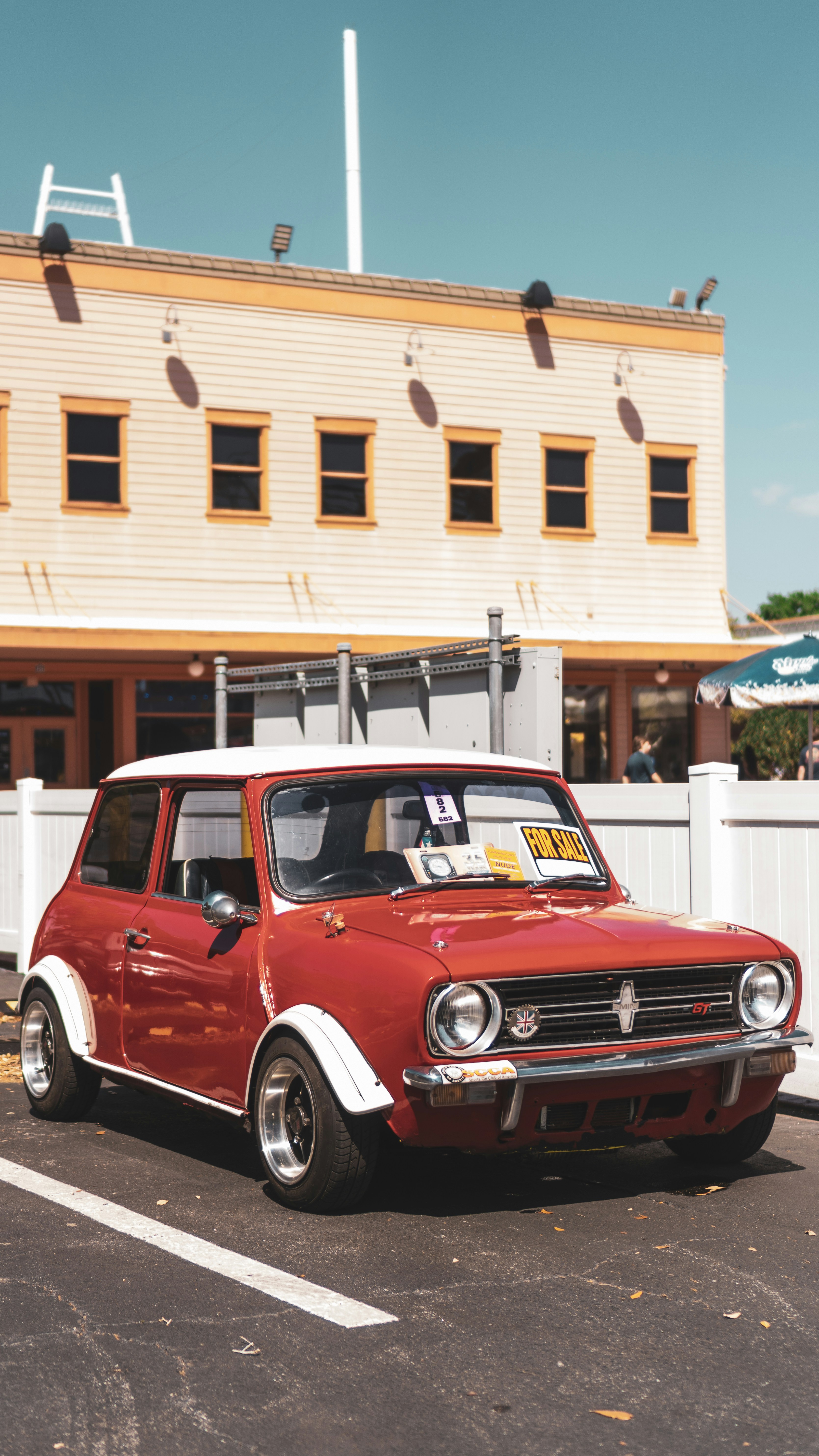 Red Classic on a Quiet Street: A Vintage Car Framed by a Sunlit Brick Building