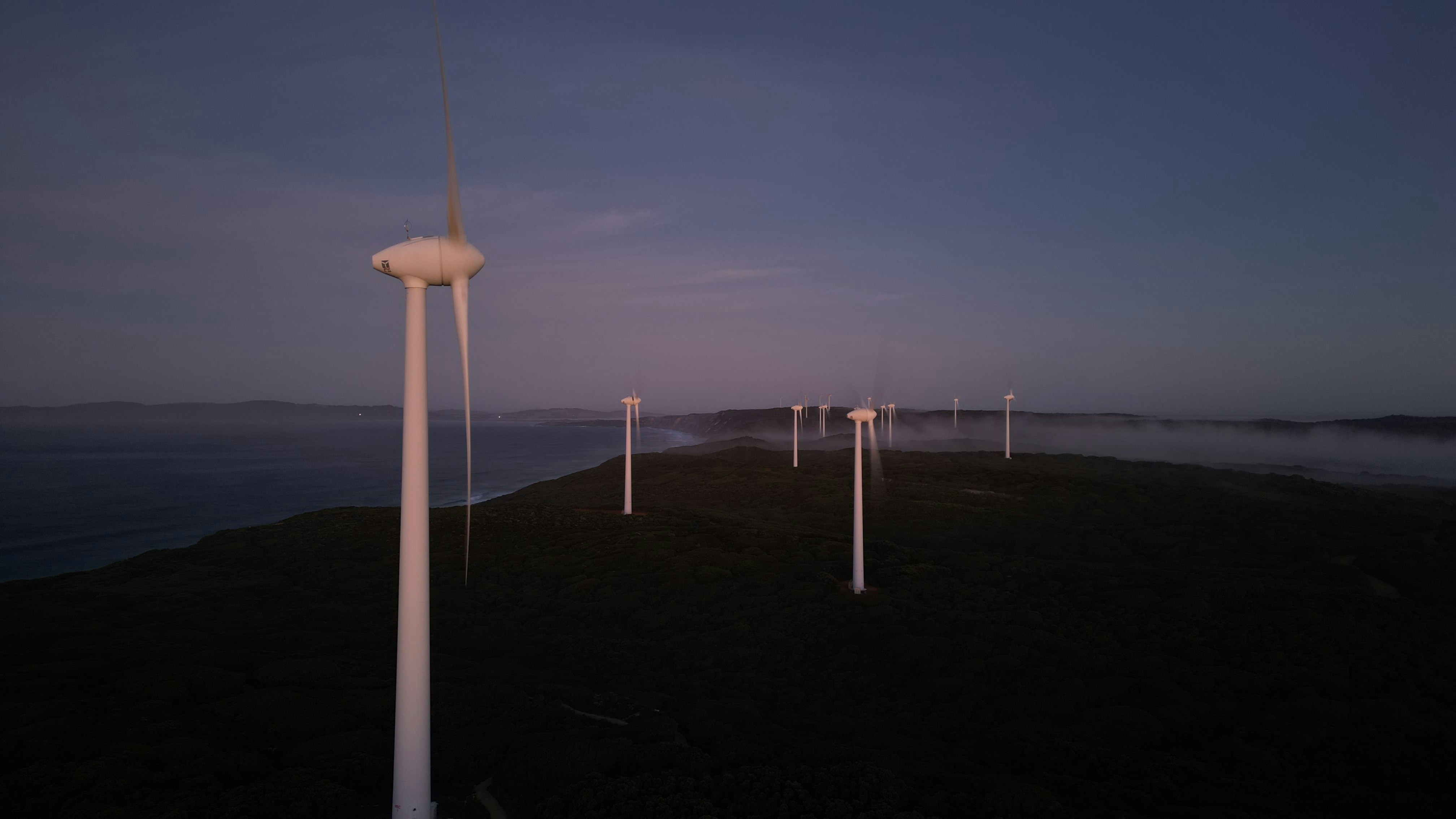 Blue Hour Ridge: Wind Turbines Standing Silent Against Misty Sea