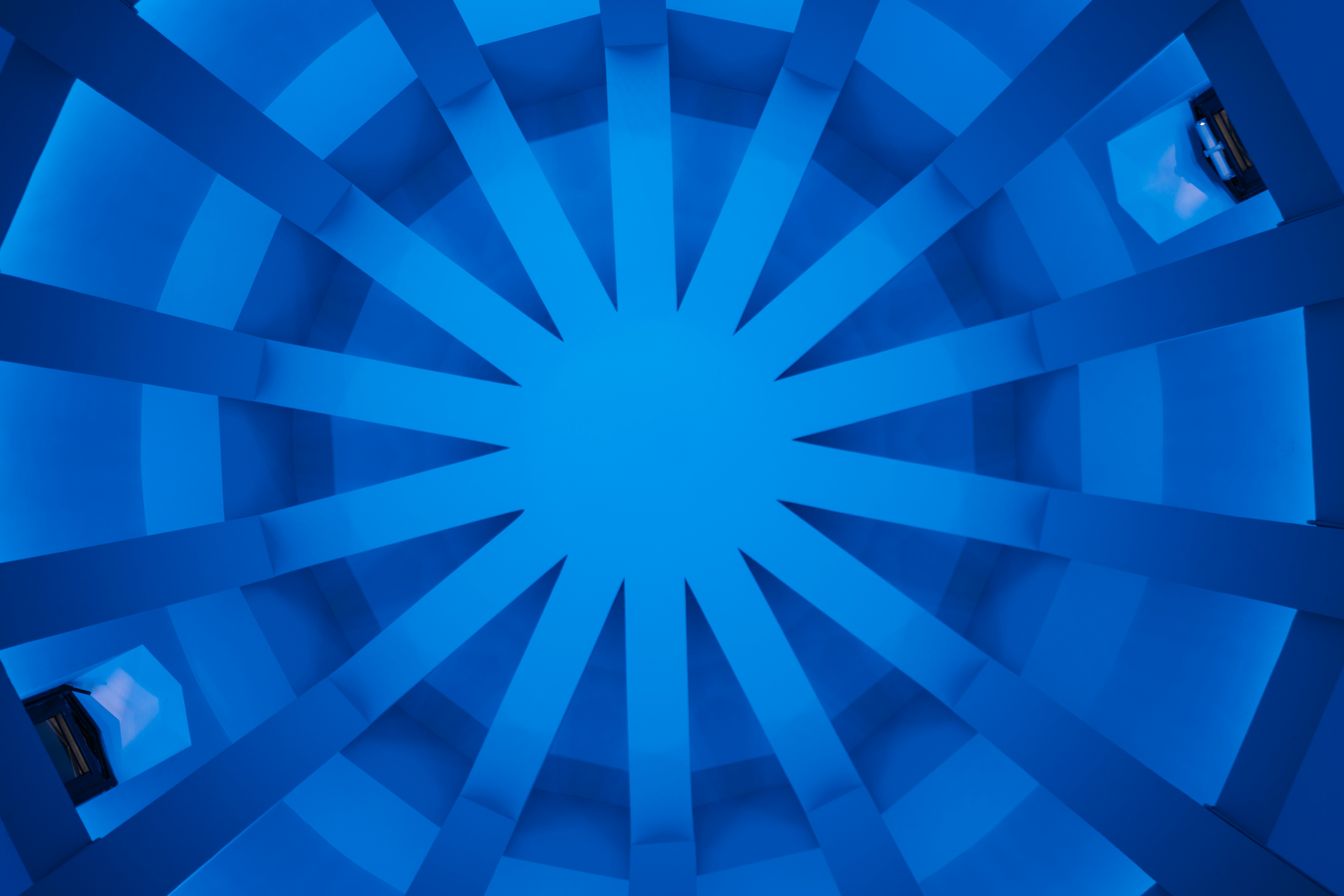Geometric ceiling design featuring radial patterns in vibrant blue tones, creating a sense of depth and perspective.