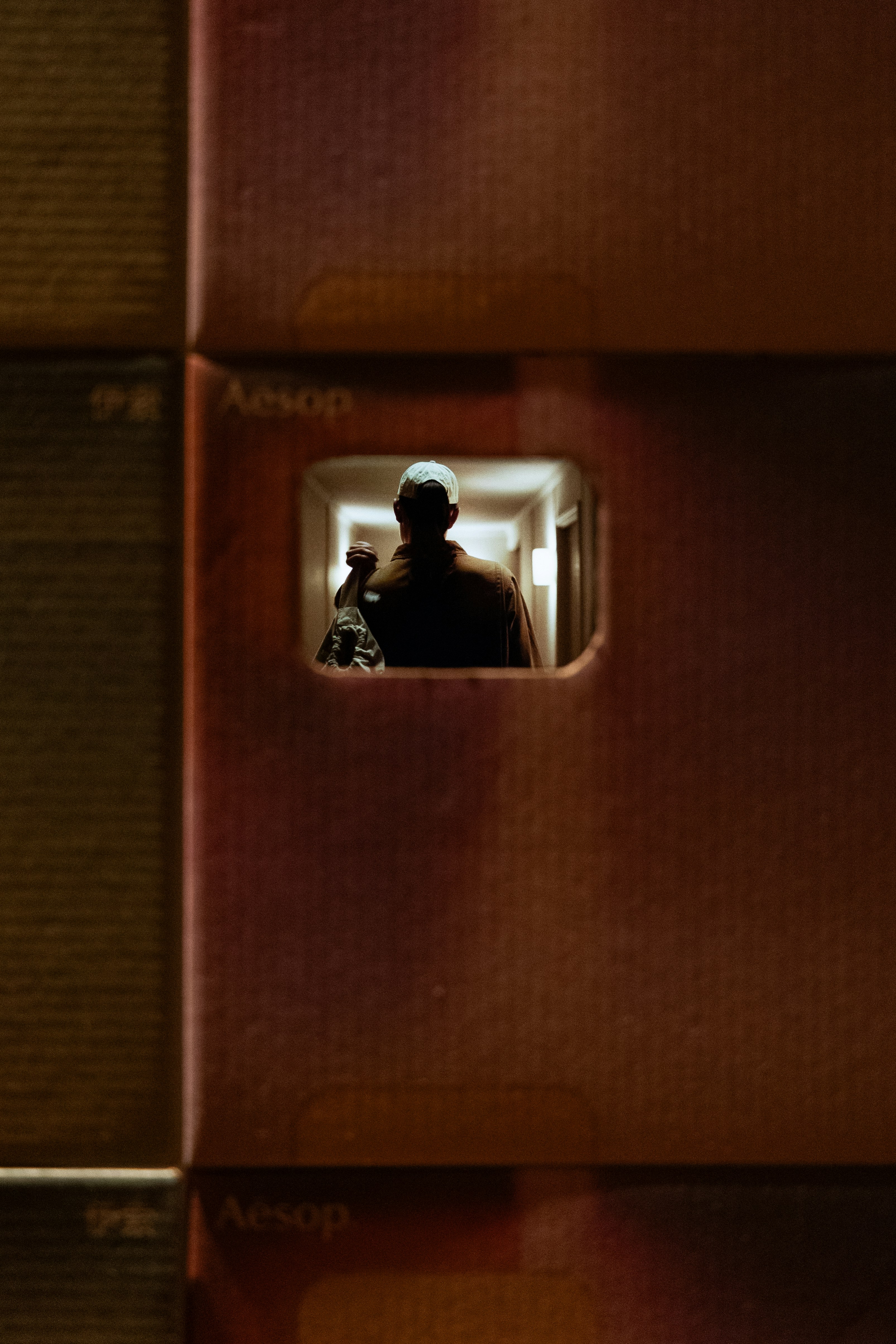 Through the Corridor of Stacks: A Backlit Figure in Cardboard Tunnels