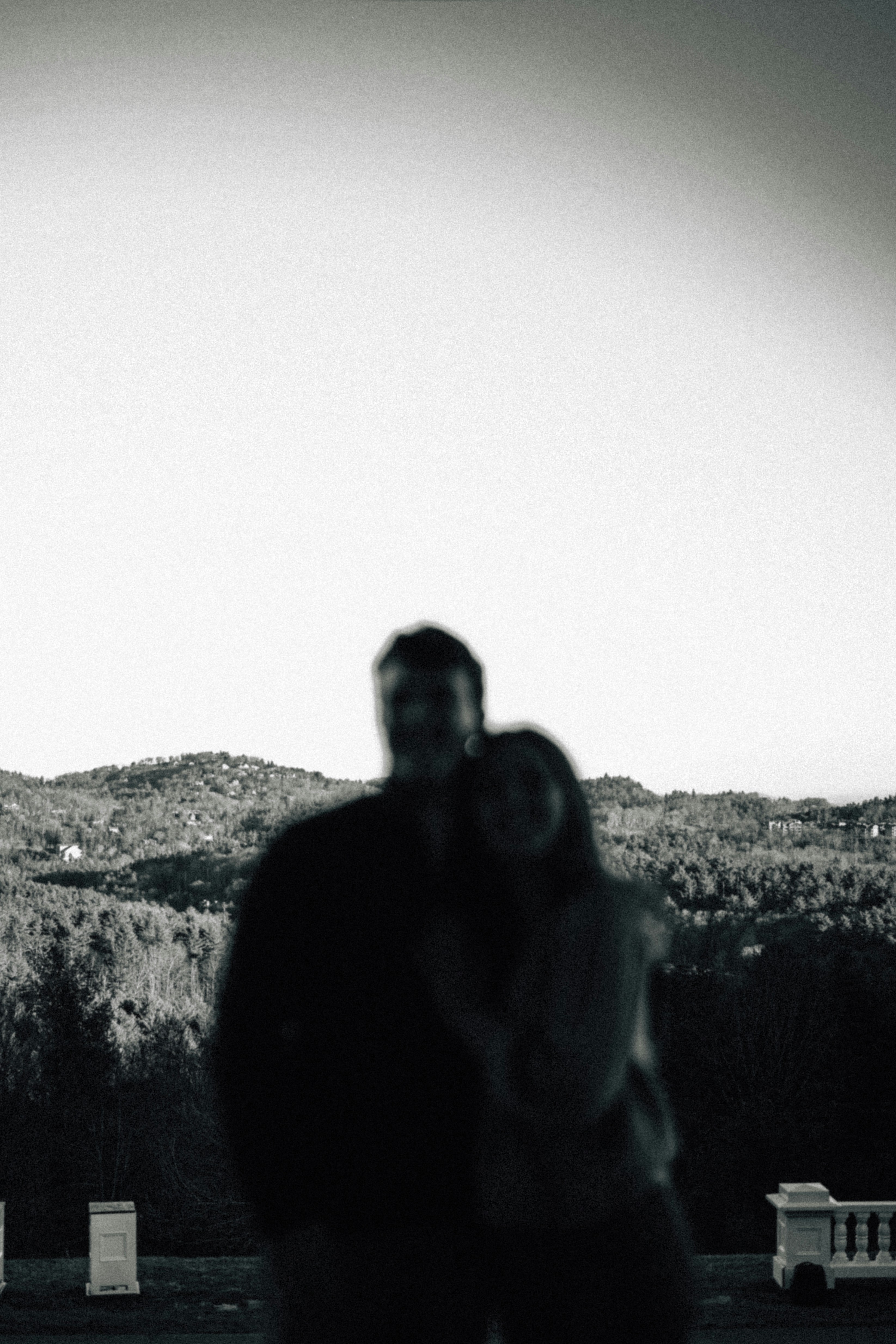 Silhouetted couple standing together with a mountainous landscape in the background during twilight.