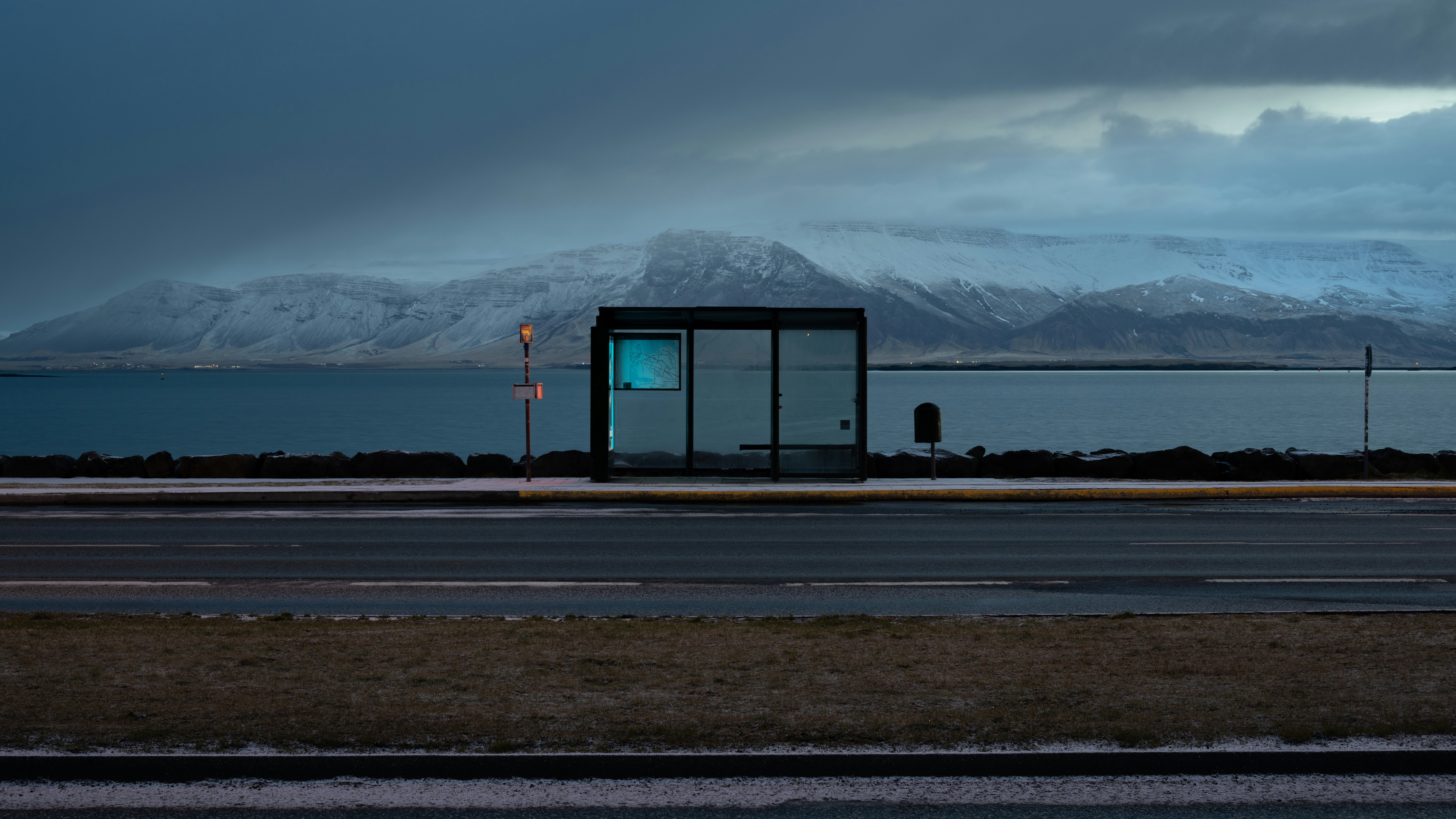 A bus stop stands before a mountainous landscape.