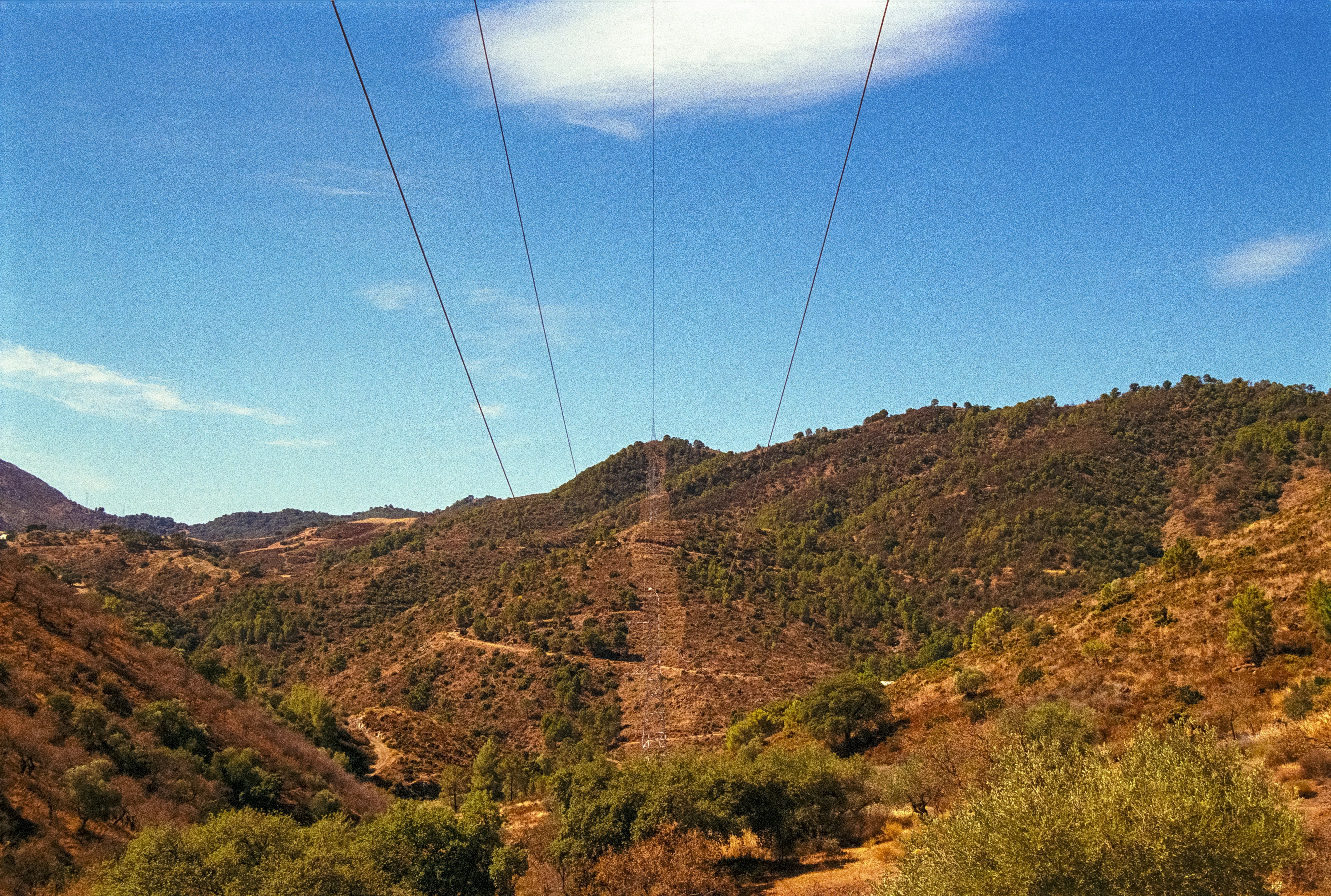 Cable car lines slice the blue canyon over sunlit hills