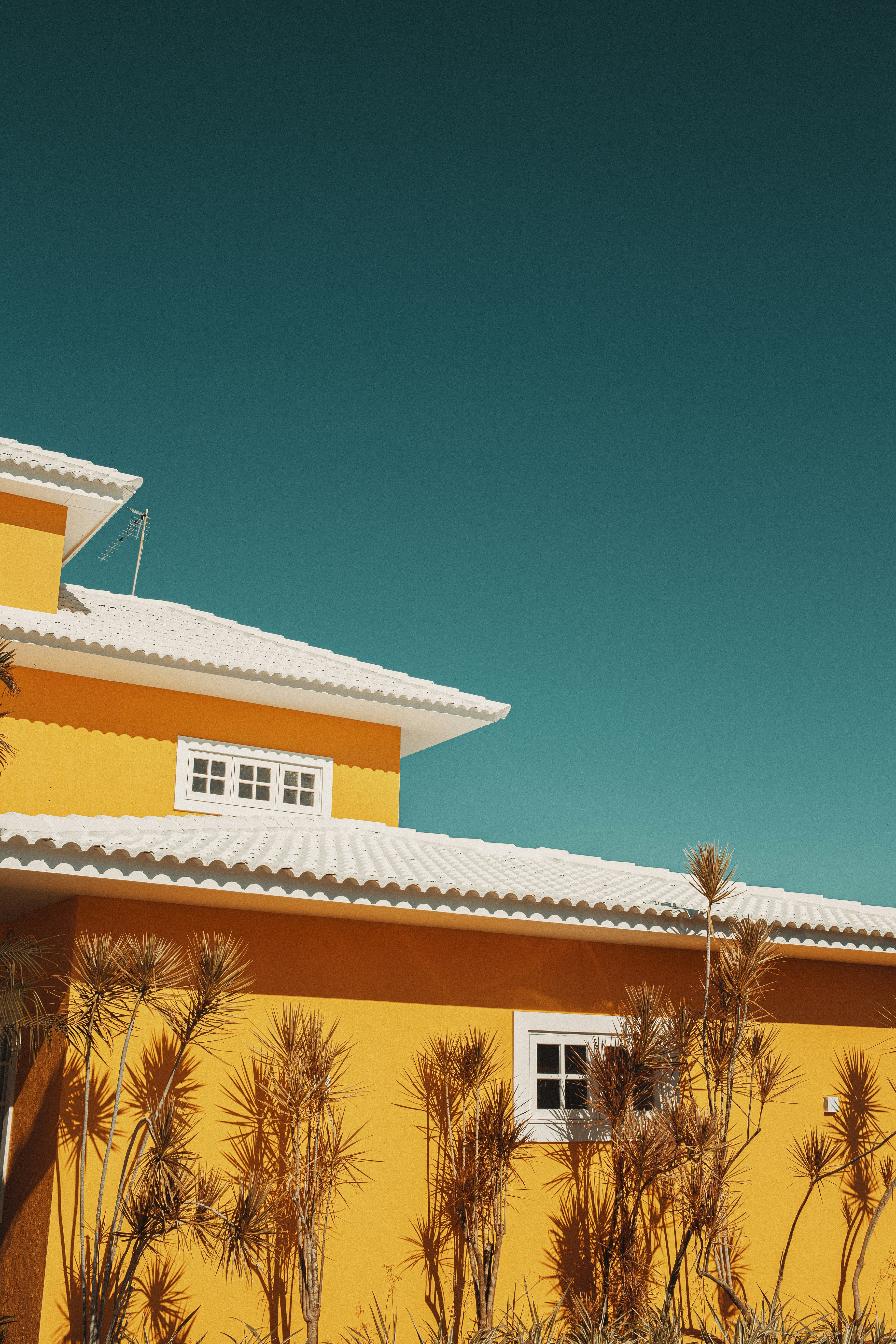 Yellow building with white roof against a teal sky. photo – Free ...