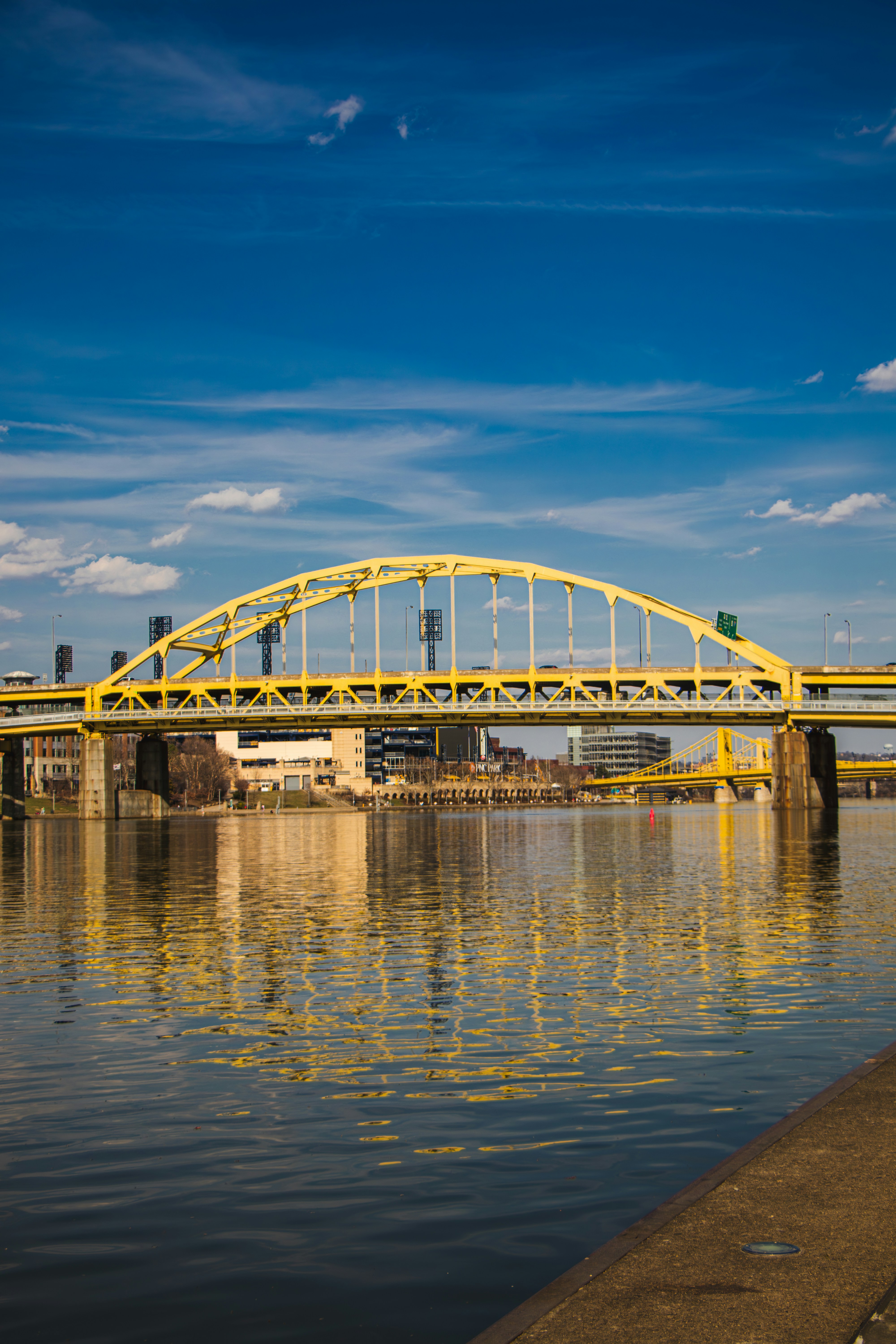 A yellow bridge is reflected in the water. photo – Free Bridge Image on ...