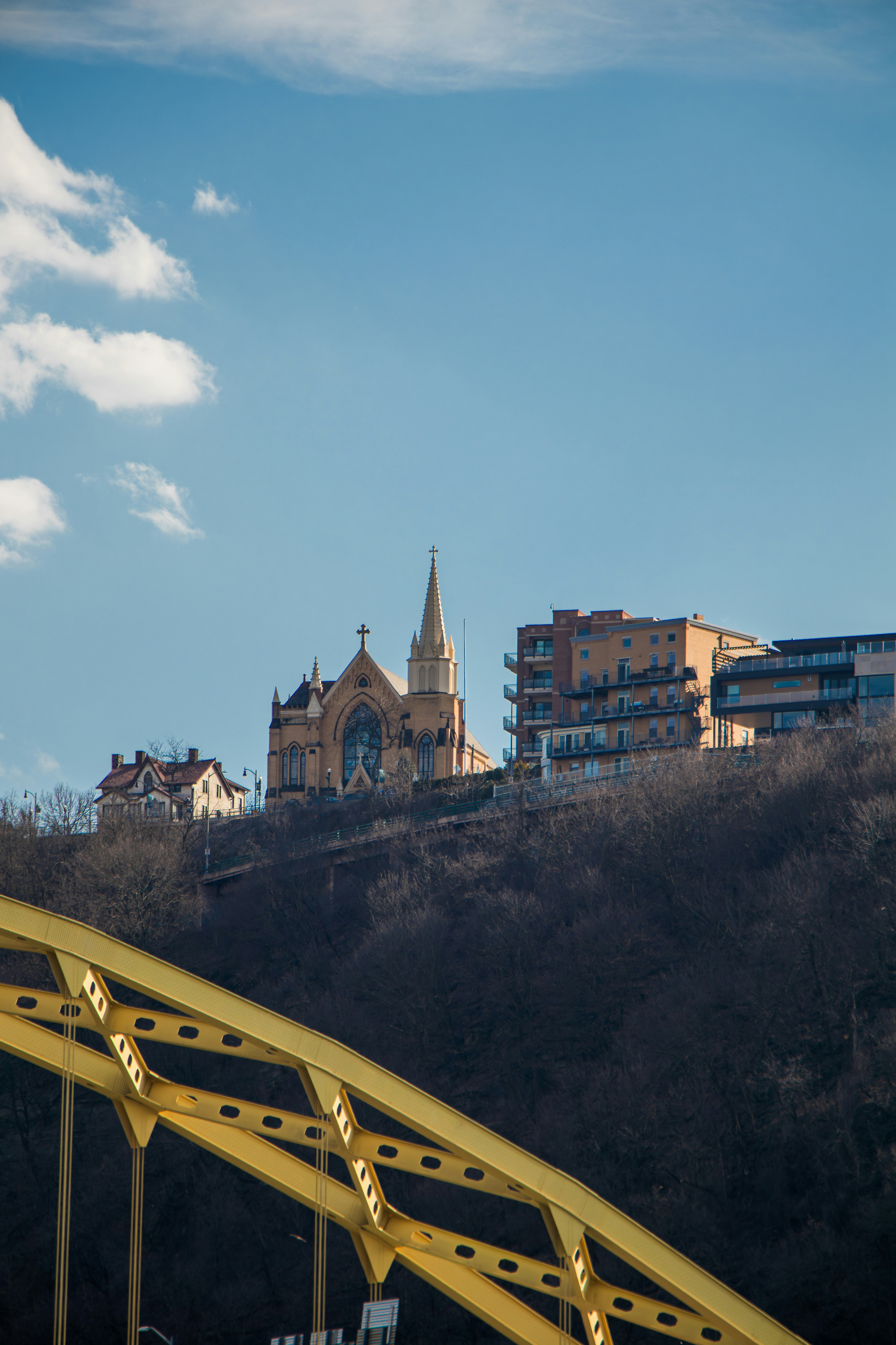 A historic church perched on a hillside, surrounded by modern buildings and a vibrant blue sky.