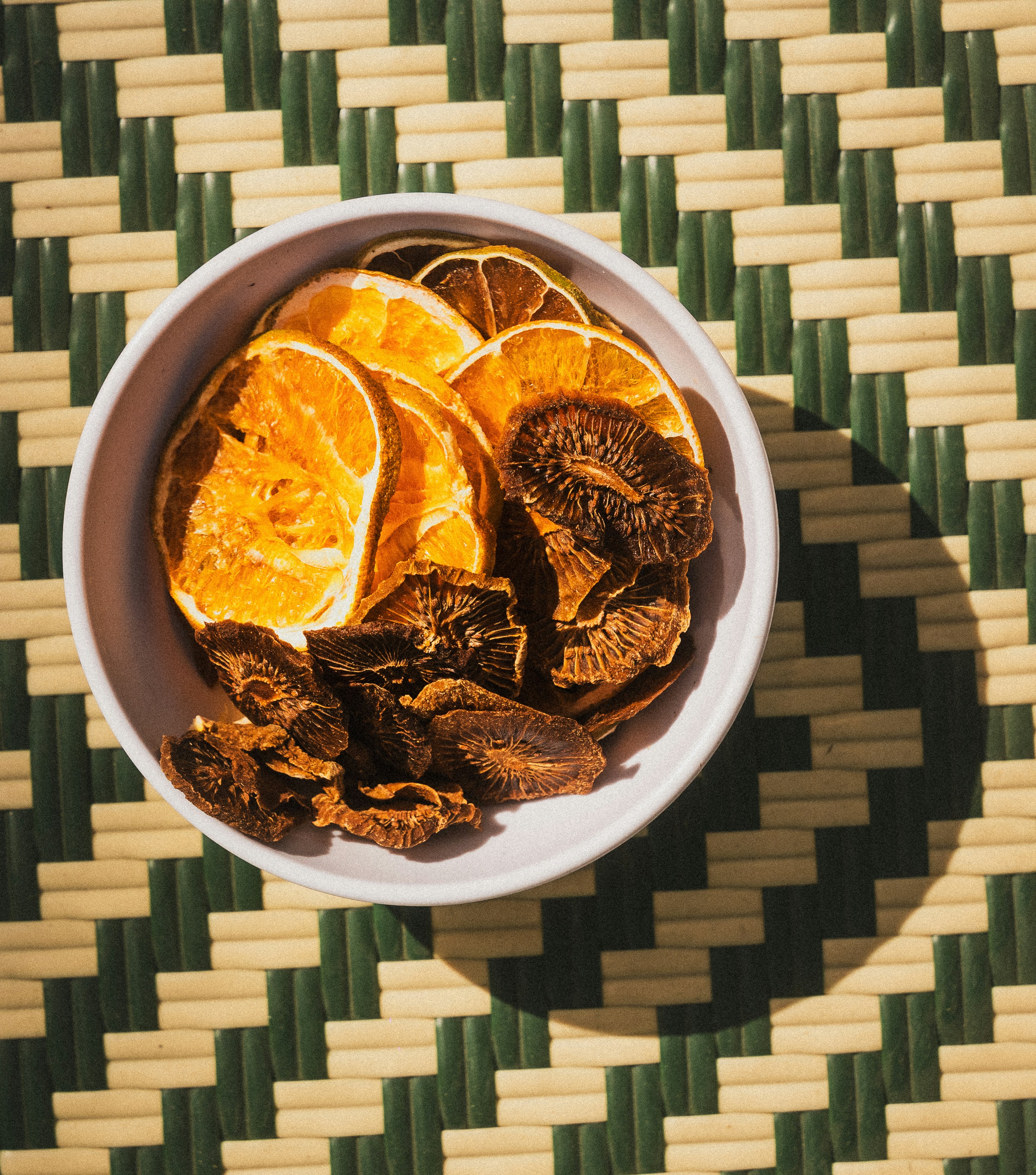 Sunlit Citrus Rings Meet Dark Reishi in a White Bowl on a Woven Mat